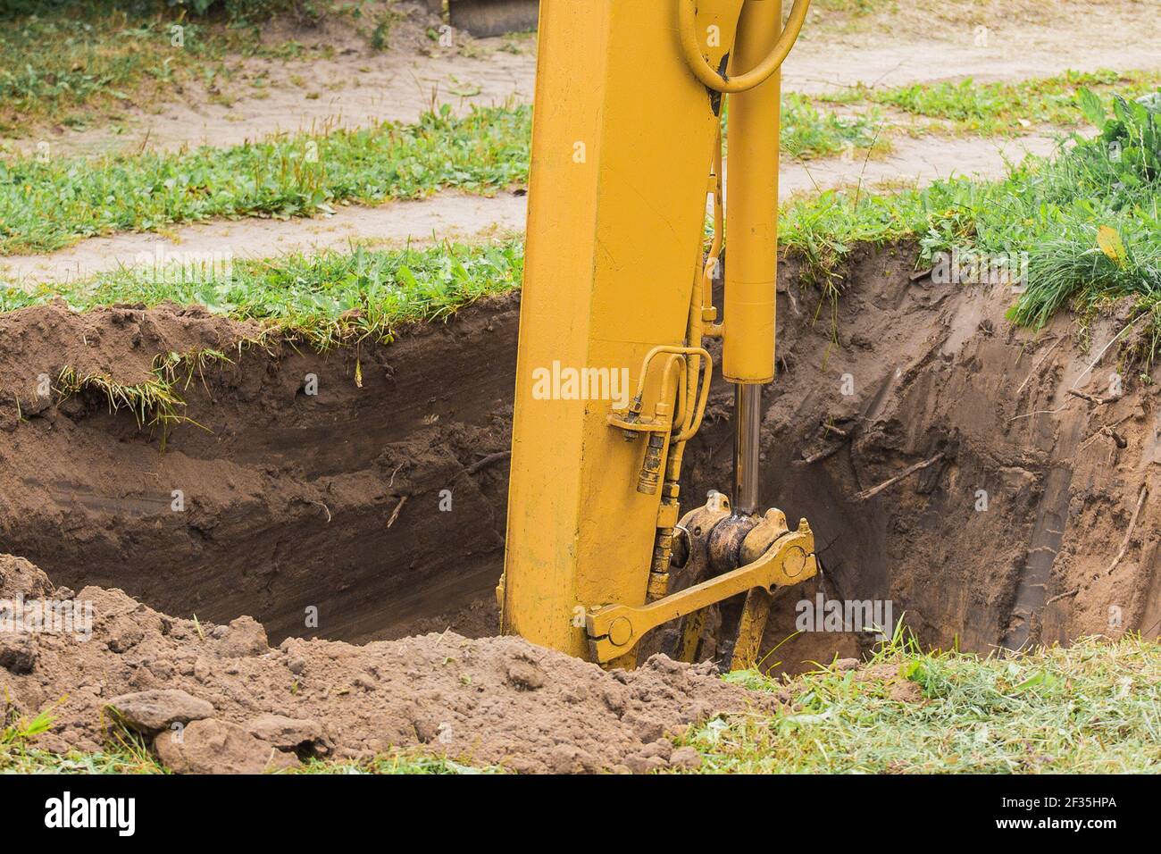 The excavator's hydraulic piston digs deep into the pit with a ...