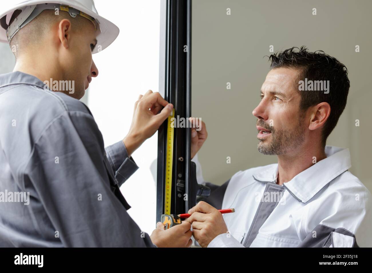 two workers make measurements of windows Stock Photo - Alamy