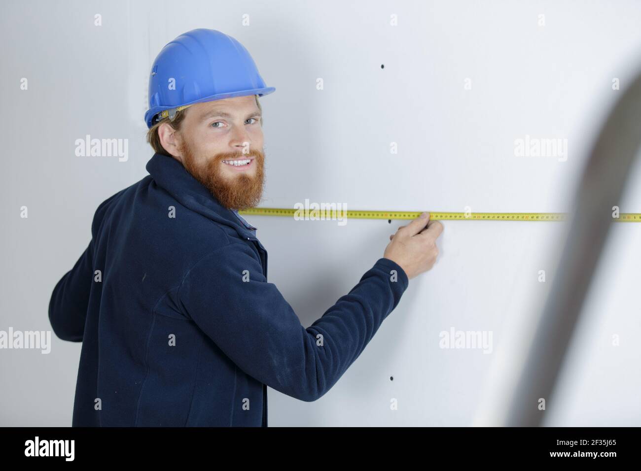 workman holding tape measure against the wall Stock Photo - Alamy