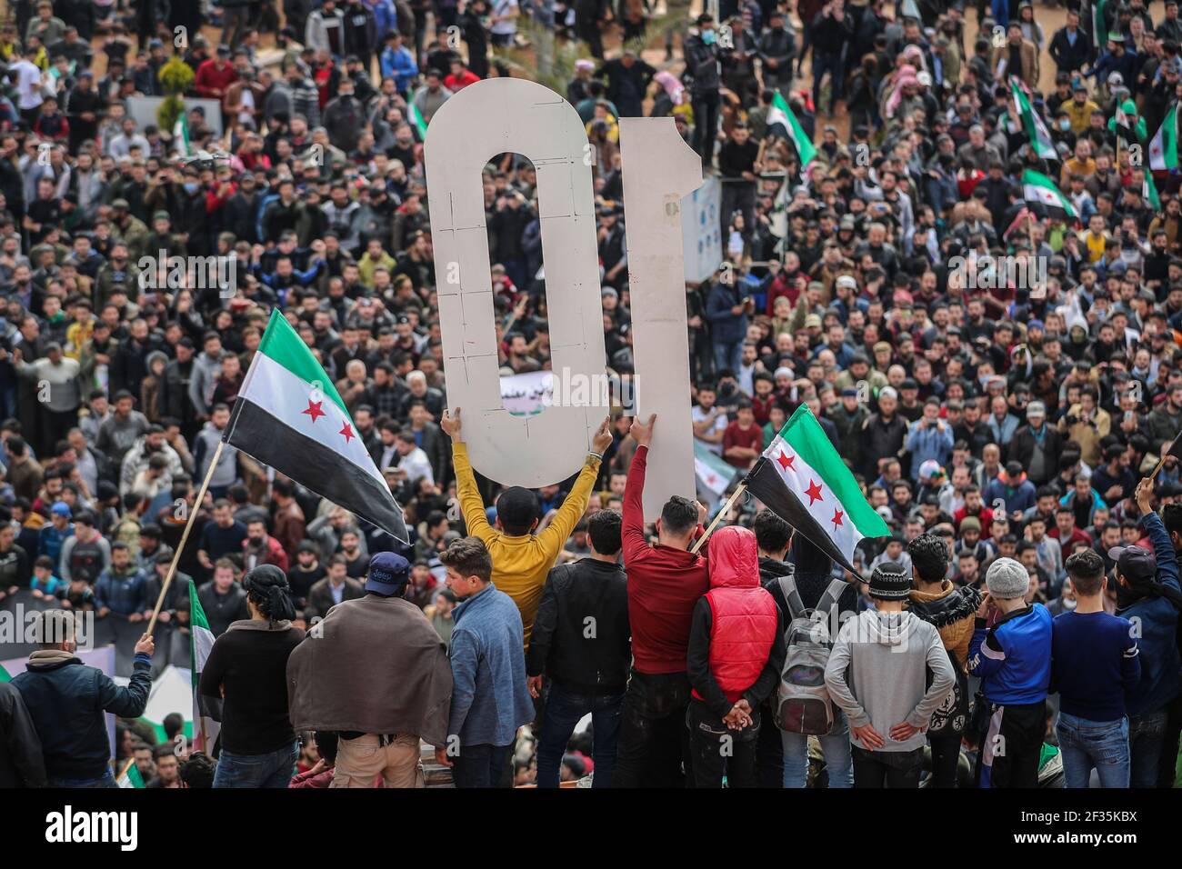 Idlib City, Syria. 15th Mar, 2021. People wave flags of the Syrian ...