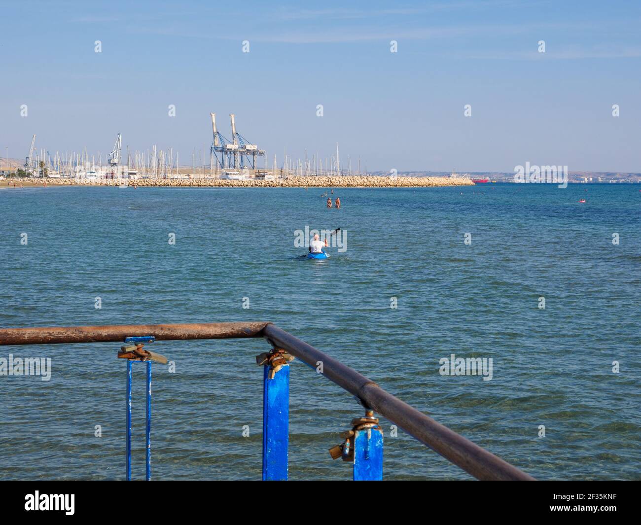 View from the pier over the man paddling in canoe and people swimming ...