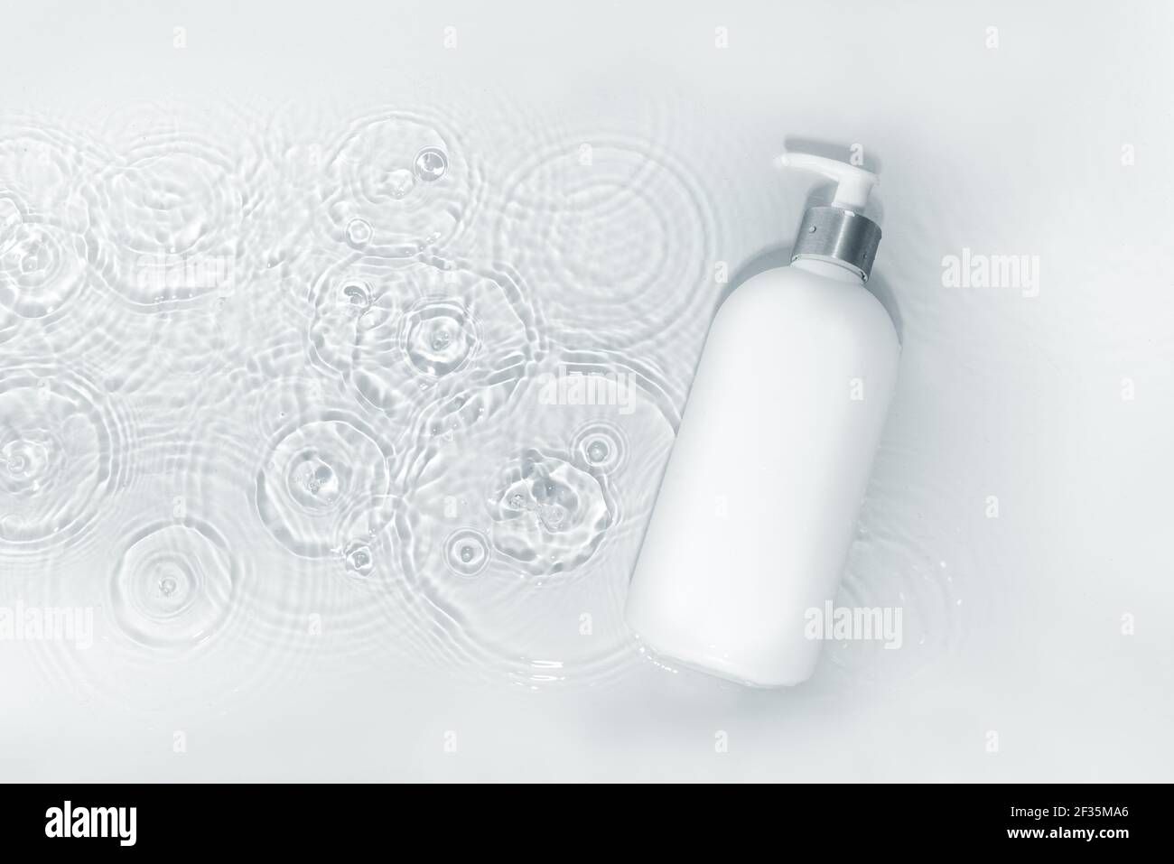 White body lotion bottle on white water background with drops, top view ...