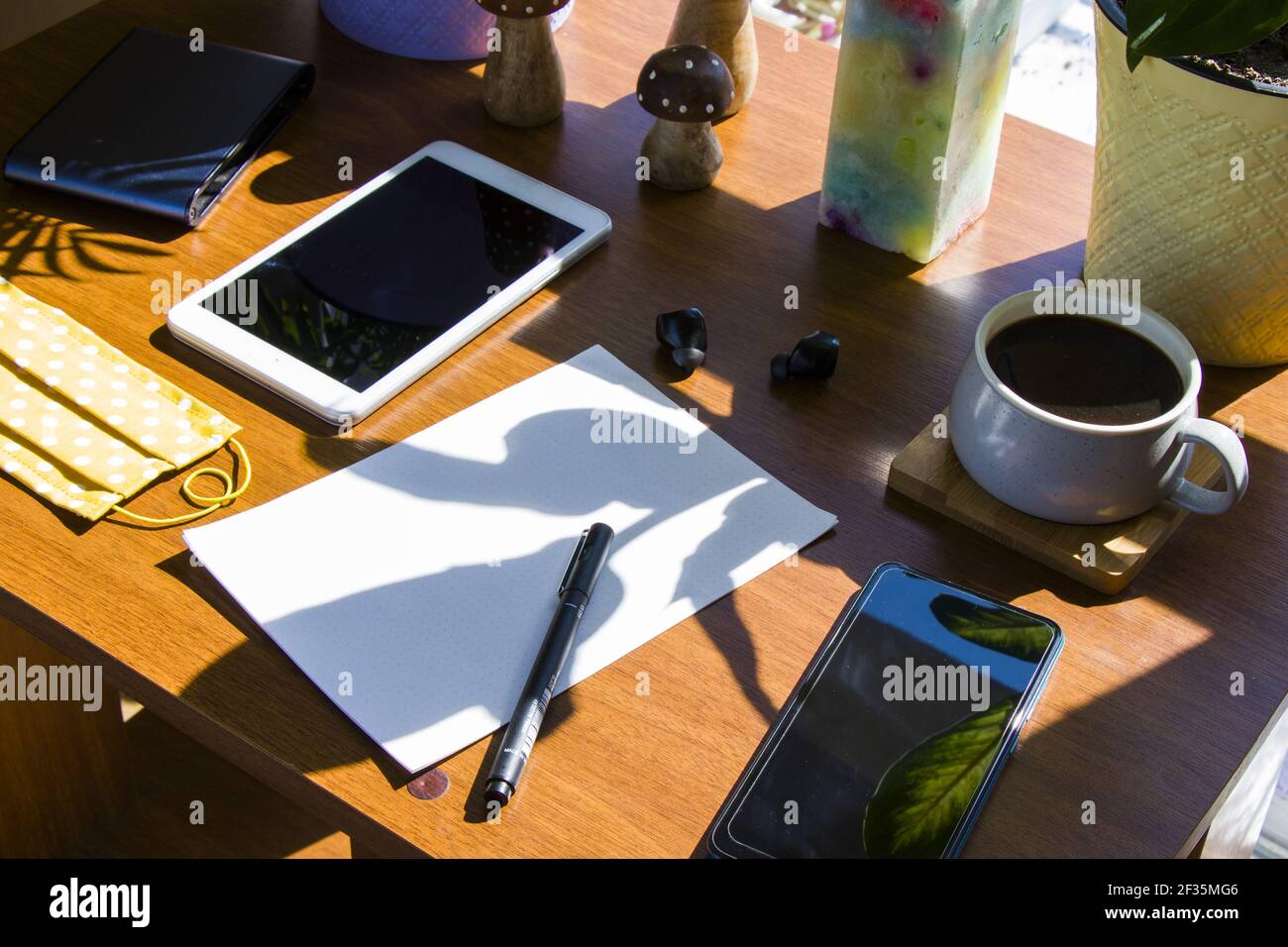 A comfy workspace with a notebook and mobile phone, coffee and plants ...