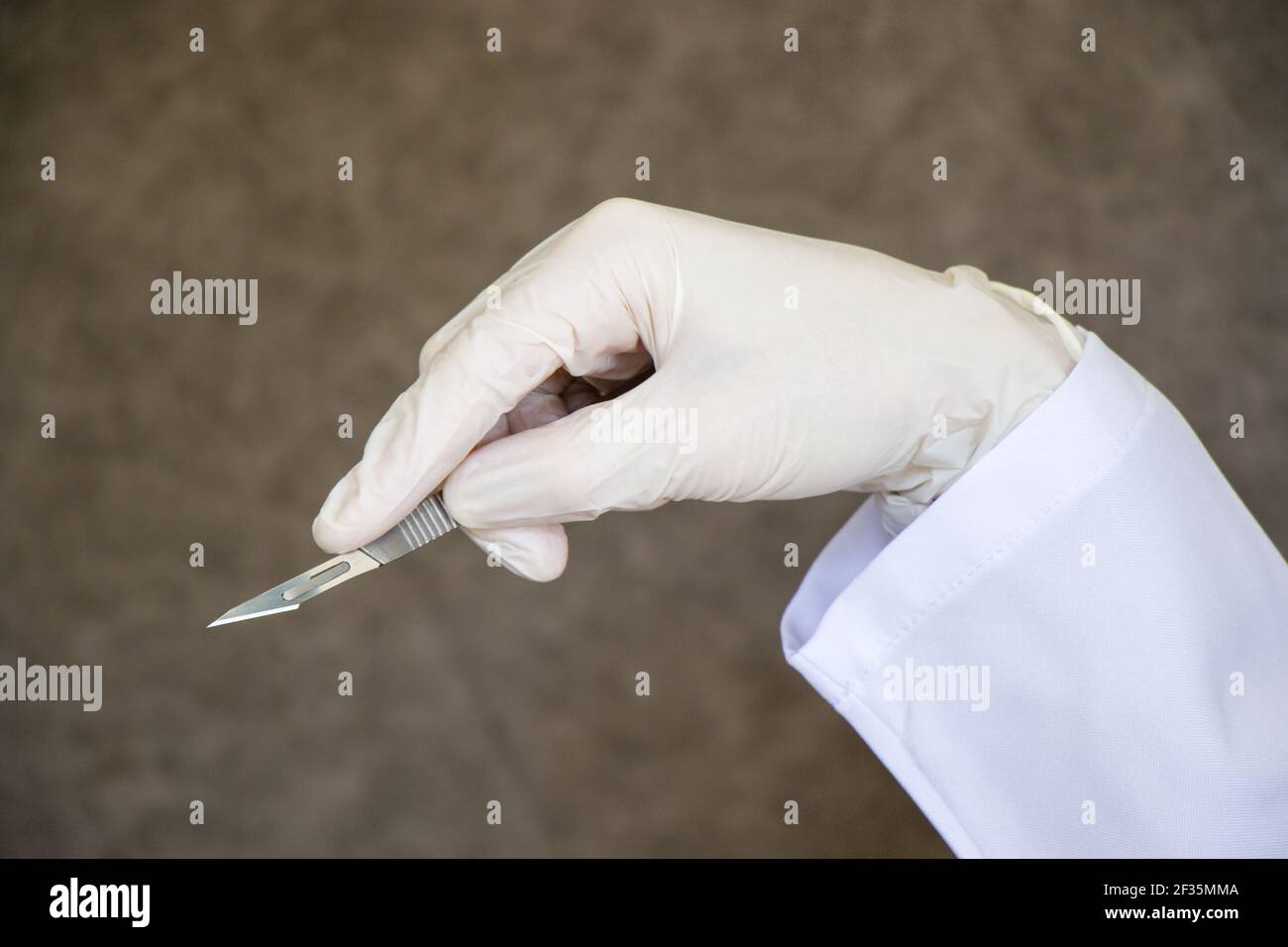 A doctor with white medical gloves holding a surgery knife in a ...
