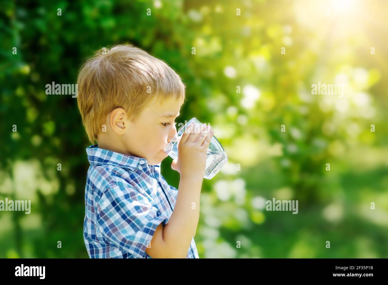 Cute boy drinking a glass of pure water in nature Stock Photo - Alamy