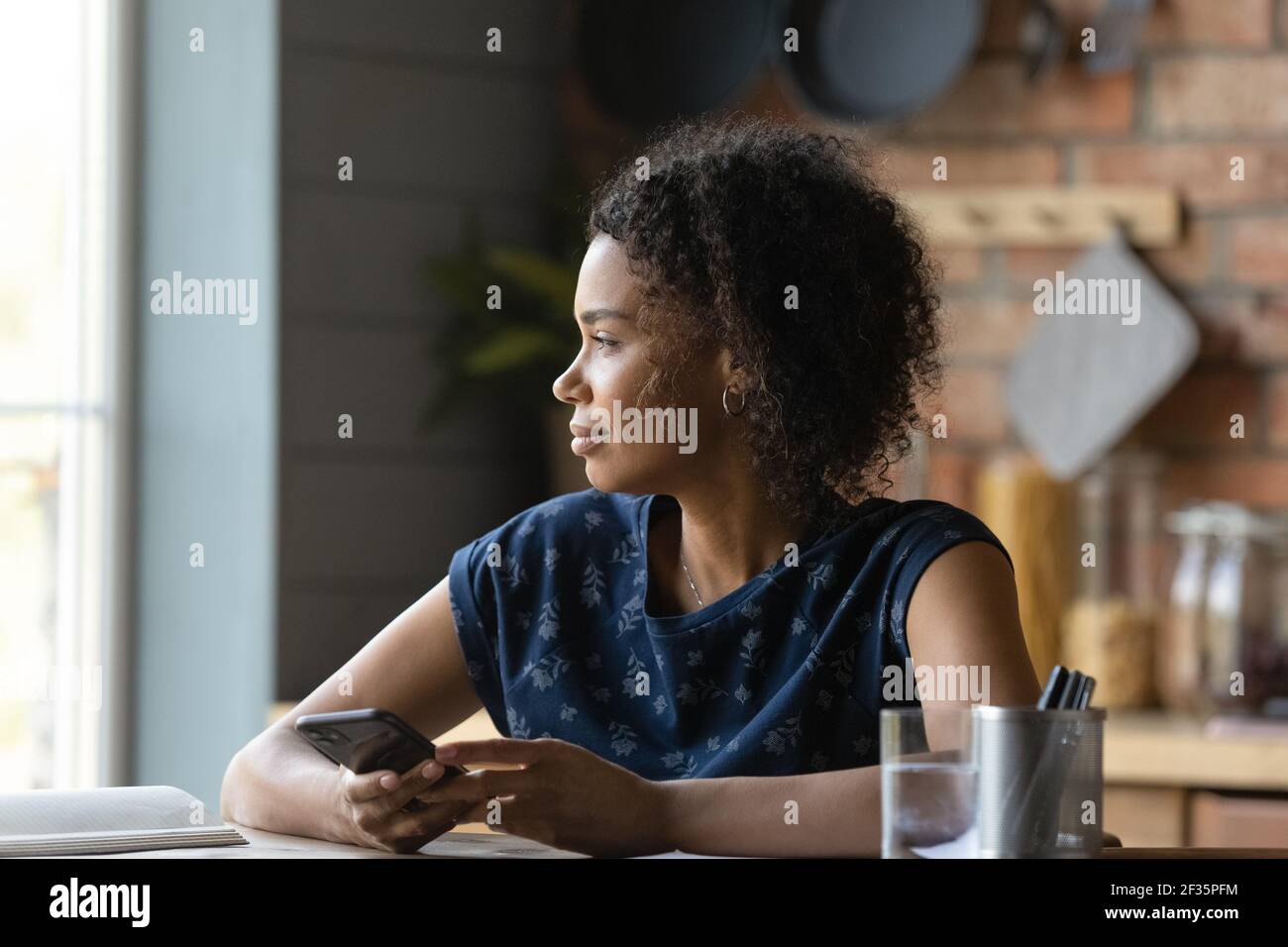 Thoughtful black lady look at window holding cellphone in hand Stock ...