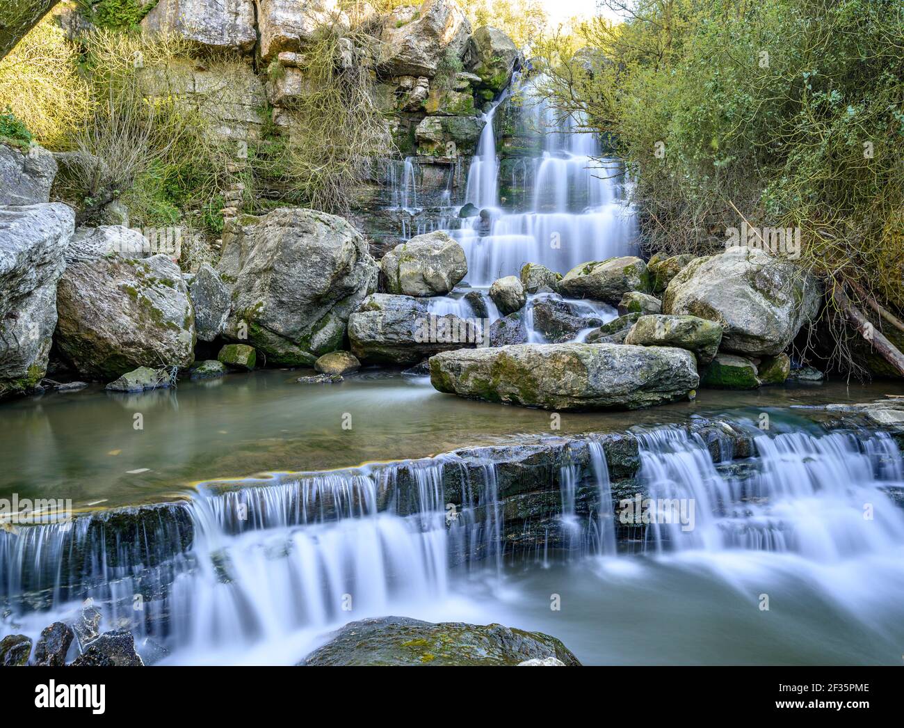 A view of a beautiful waterfall with trees alongside Stock Photo - Alamy