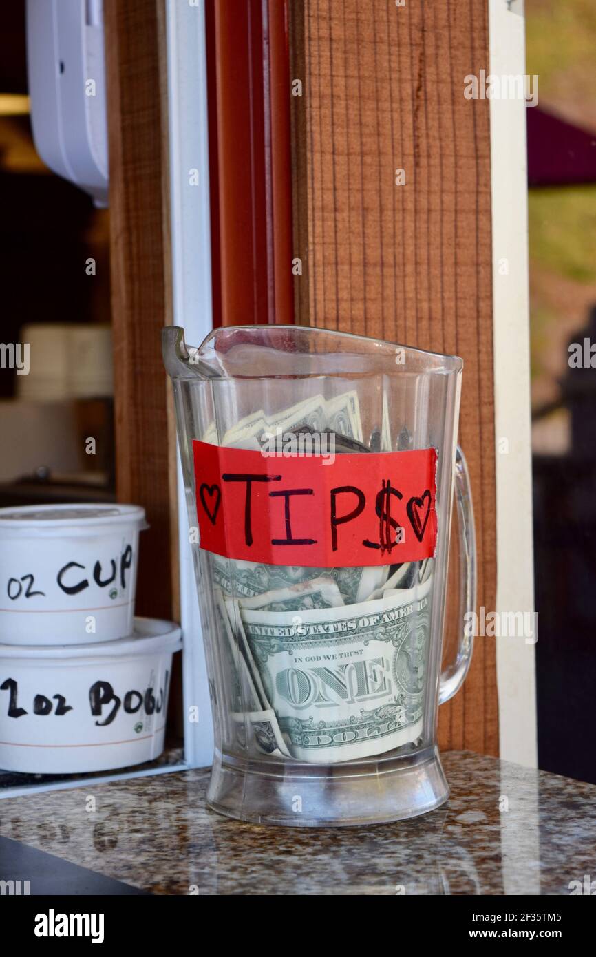 A vertical shot of tips jar on an outside window counter of a ...