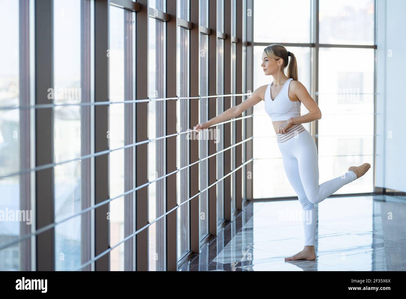 Pretty woman in white sportswear in gymnastics room. Athletic girl ...