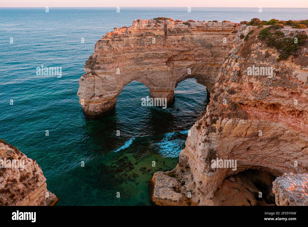 An aerial view of natural rock formations and a turquoise shiny sea of ...