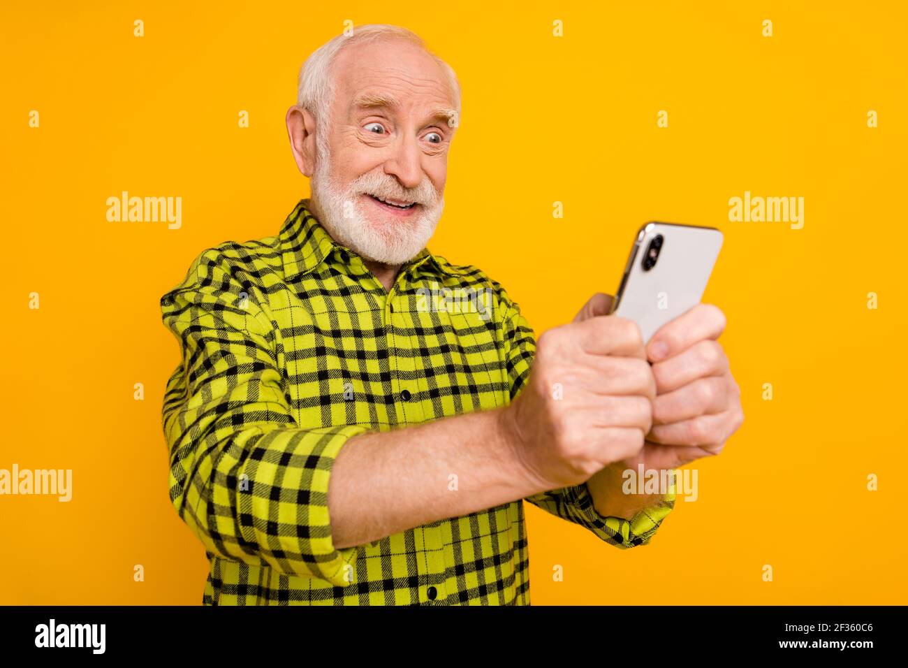 Photo of excited senior man hold telephone look screen wear plaid green ...