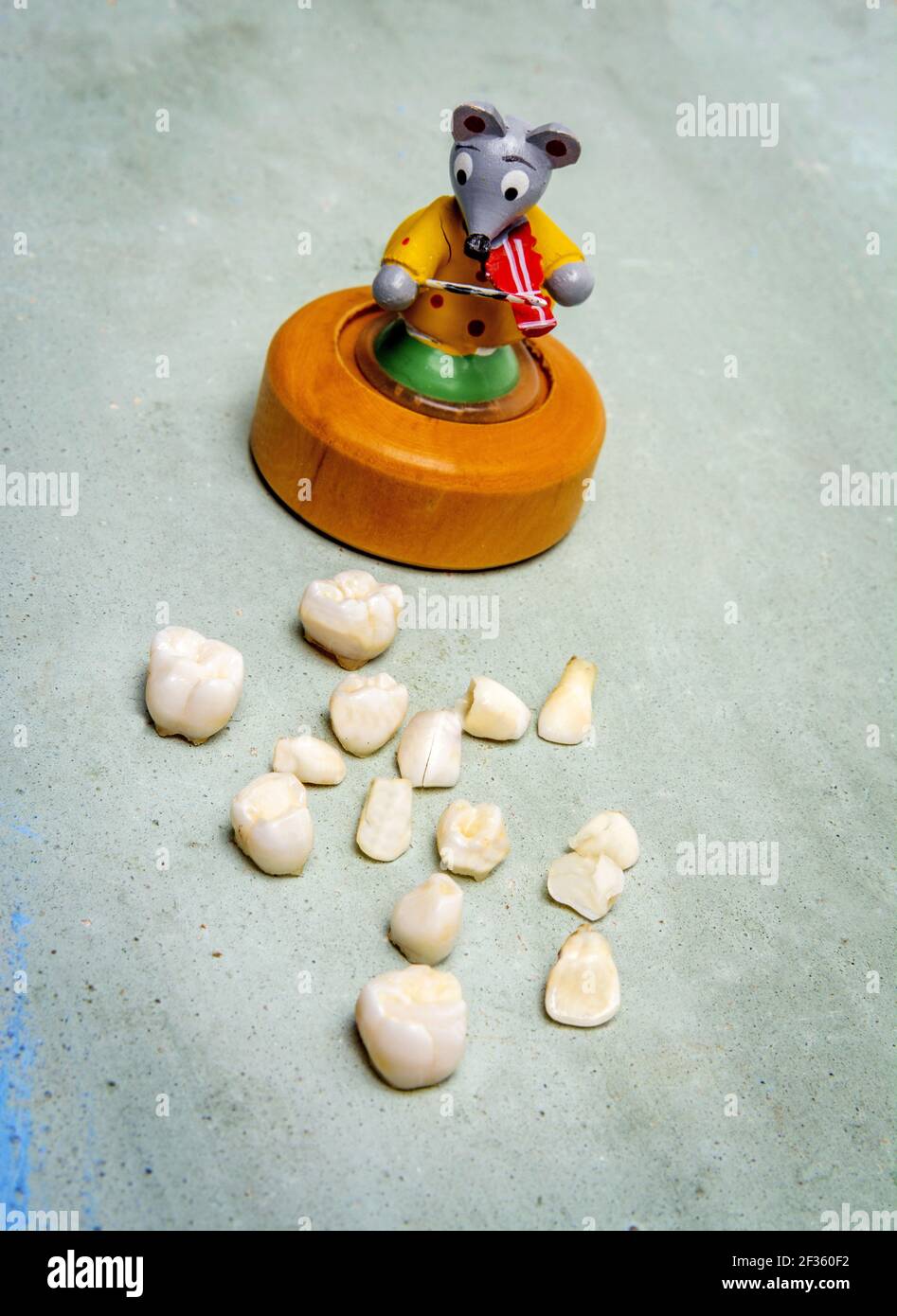 A vertical shot of a mouse figure with milk teeth on a gray surface ...