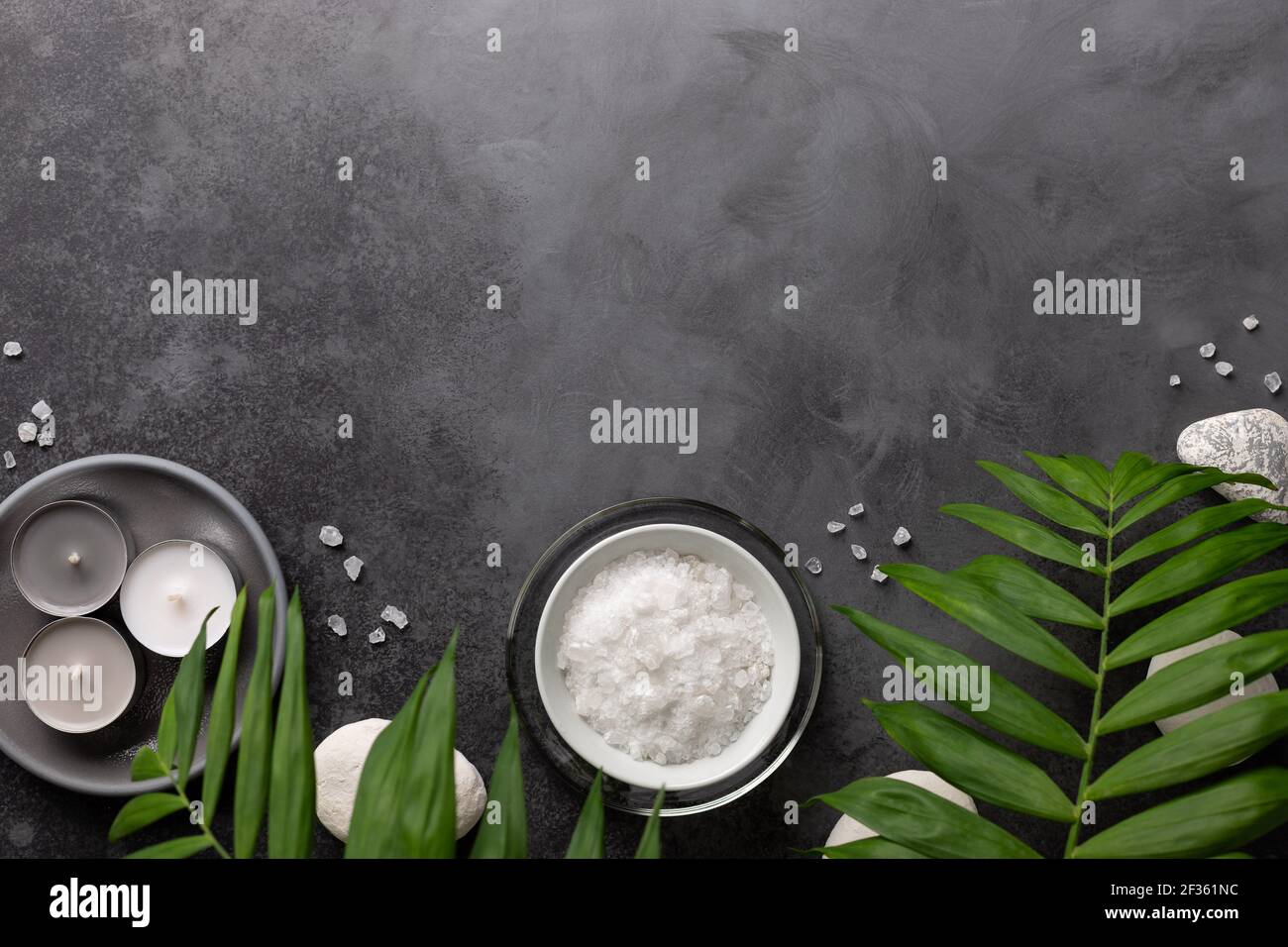 spa border with natural sea salt in a bowl, candles, stones and green ...