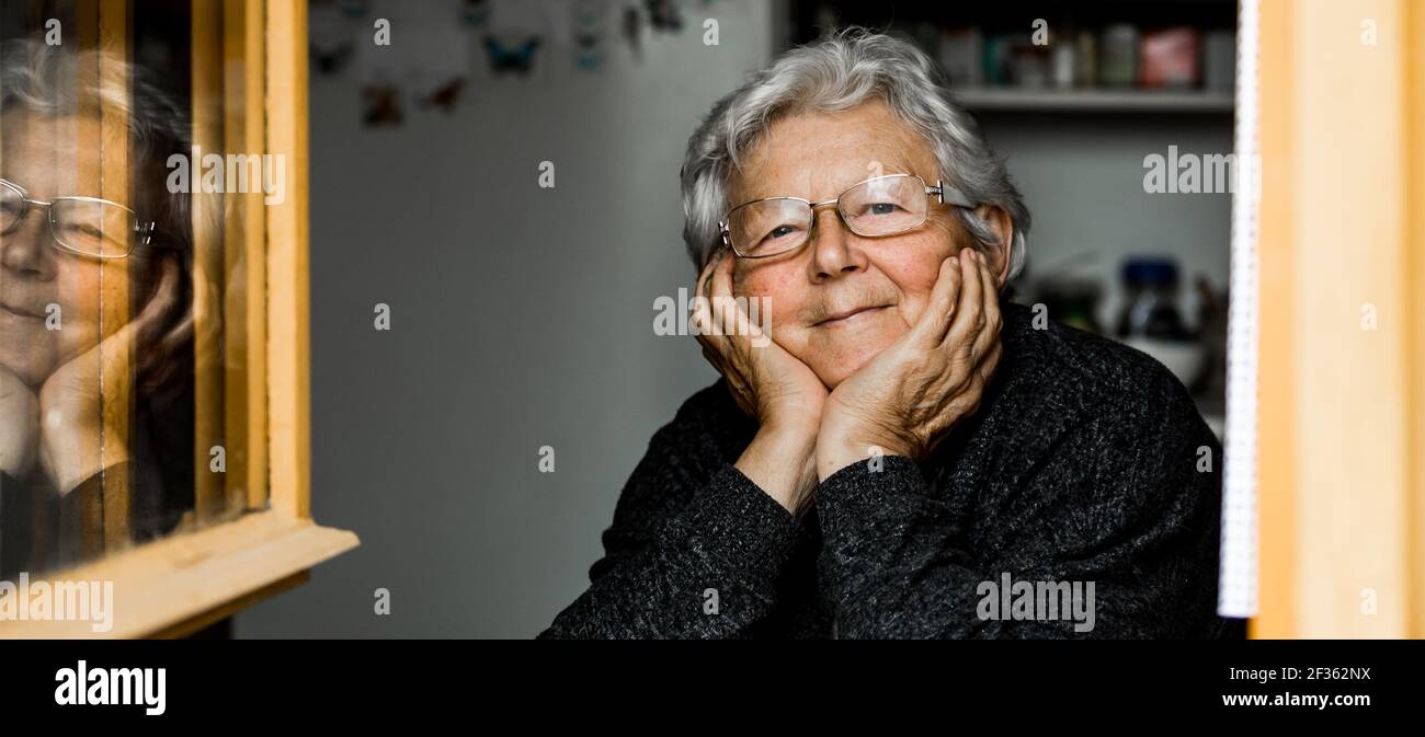 Portrait of lovely senior woman looking outside of the window, carefree ...