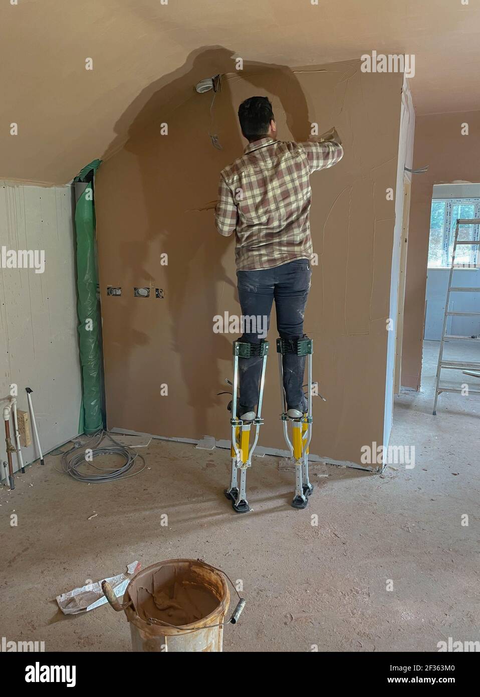 Workman on Stilts Plastering a Wall in a Building Renovation in Rural ...