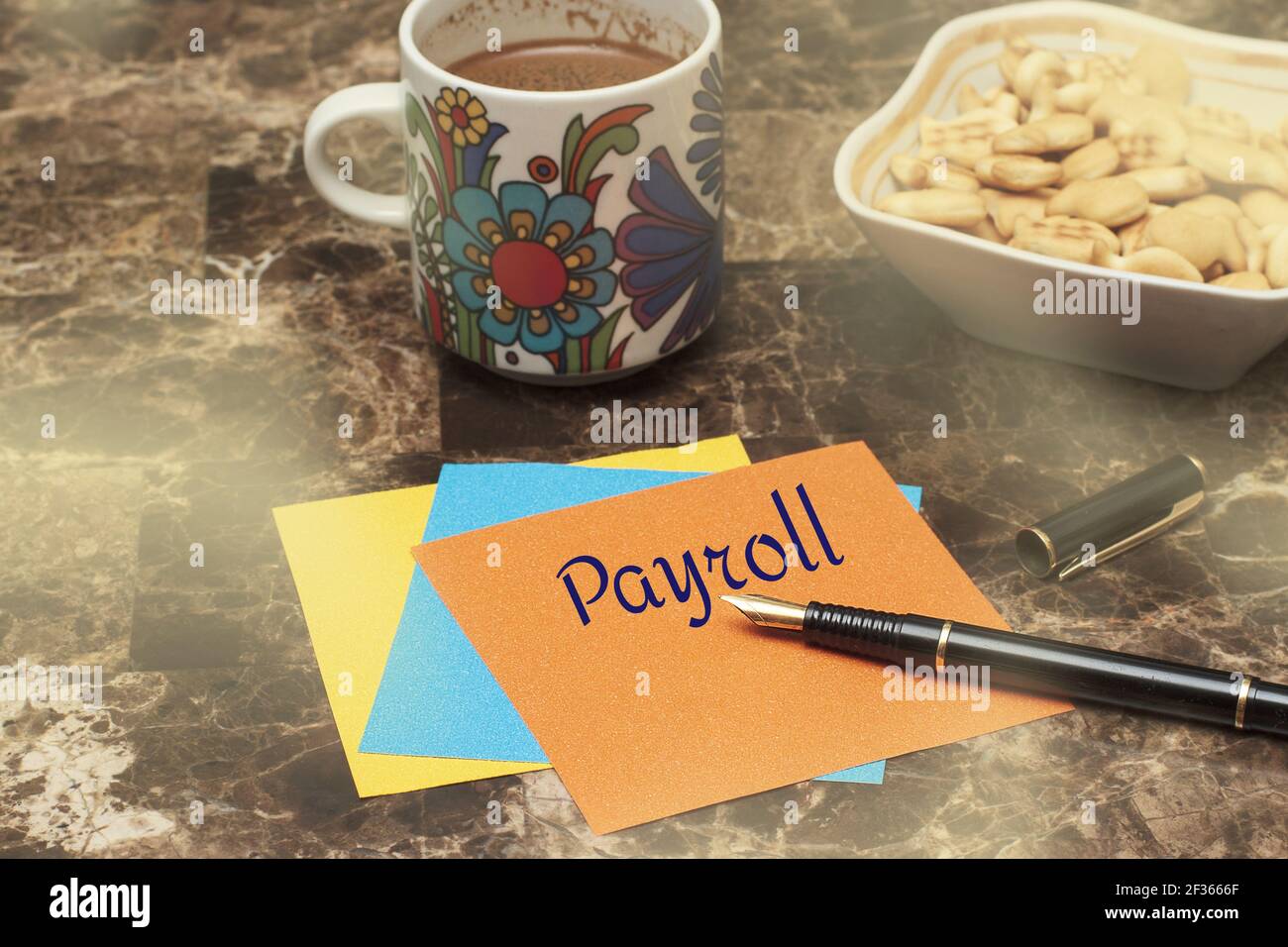 PAYROLL write on sticker on marble table, mug of coffee and bowl of ...