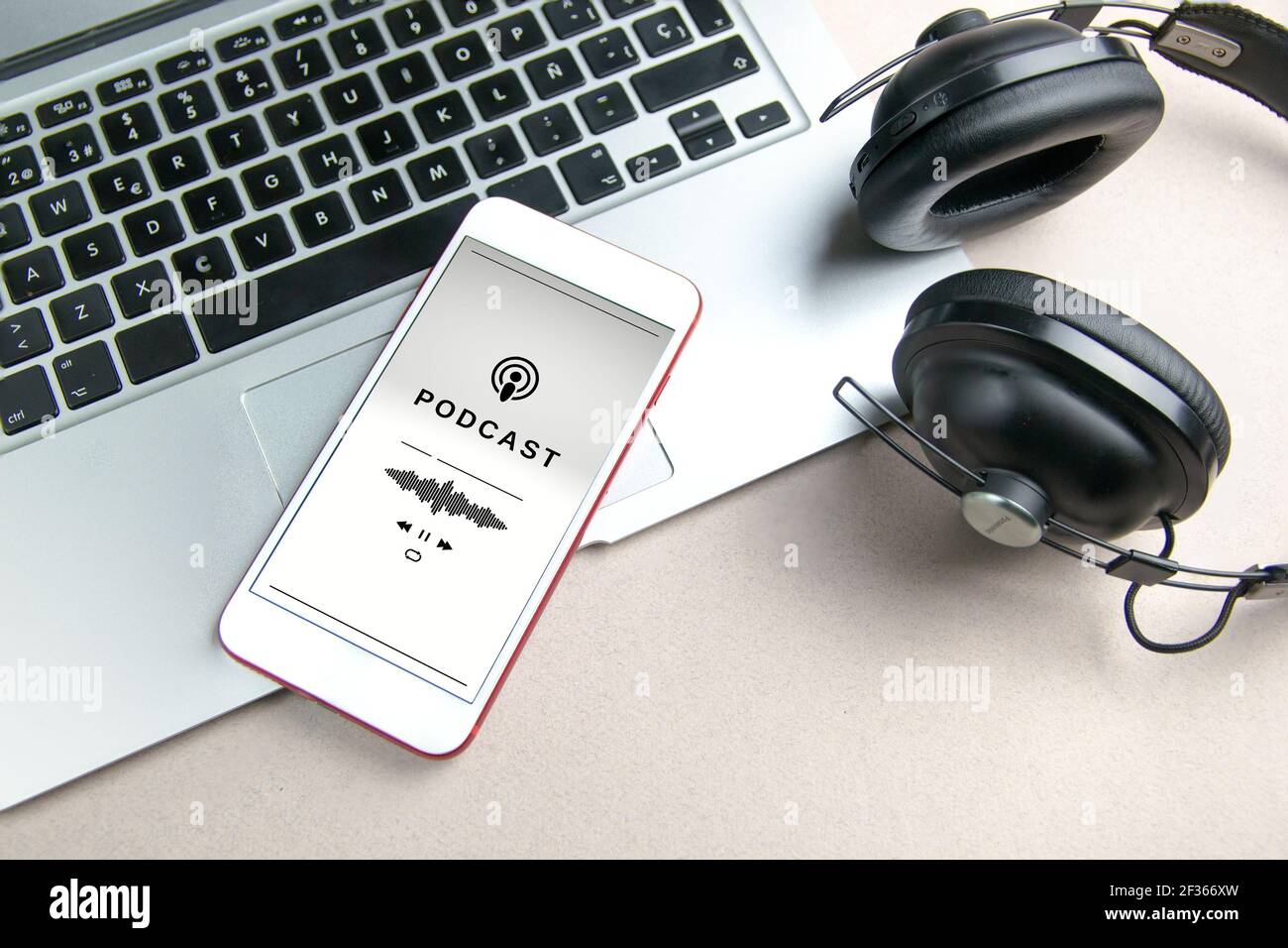 Smartphone playing a podcast. Mobile phone, laptop and headphones on ...