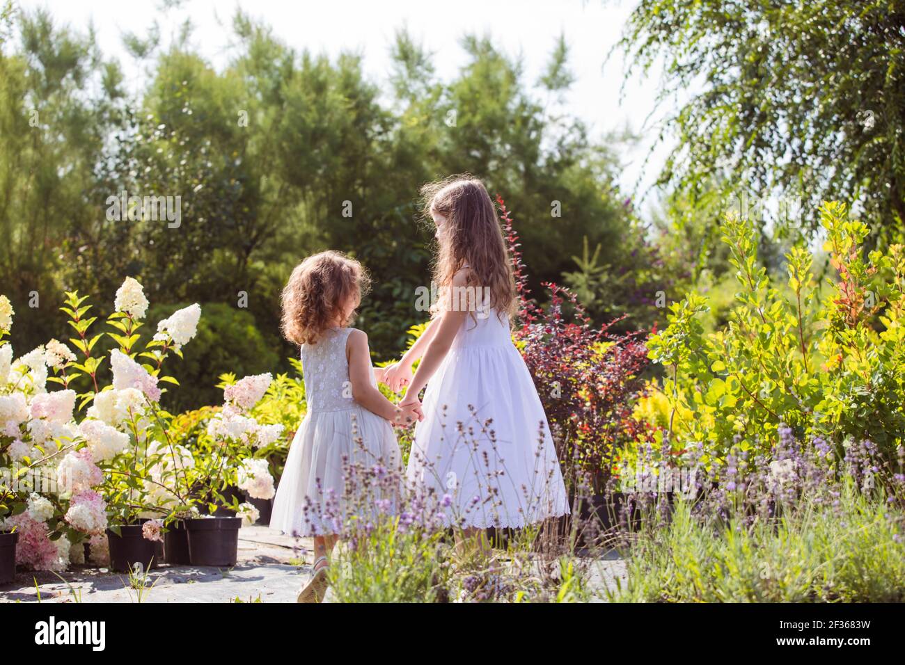Little girls dancing among wonderful blooming flowers Stock Photo - Alamy