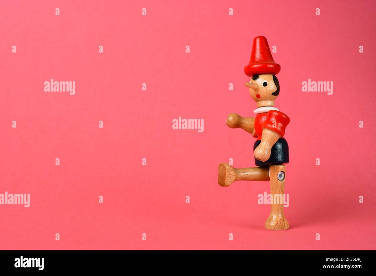 Wooden puppet depicting Pinocchio walking on a pink background Stock ...