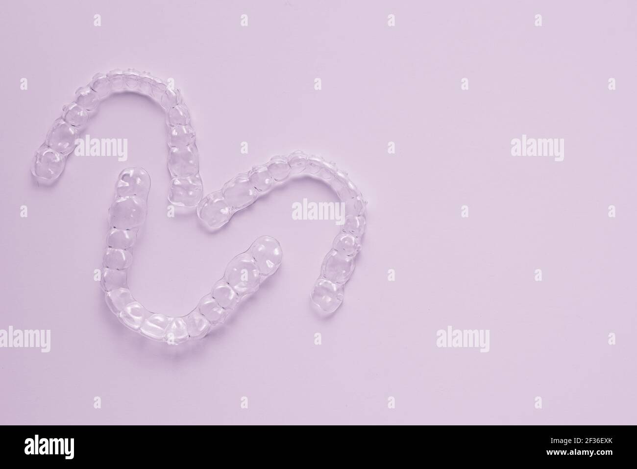 Invisible aligner teeth retainers on a pink background Stock Photo - Alamy