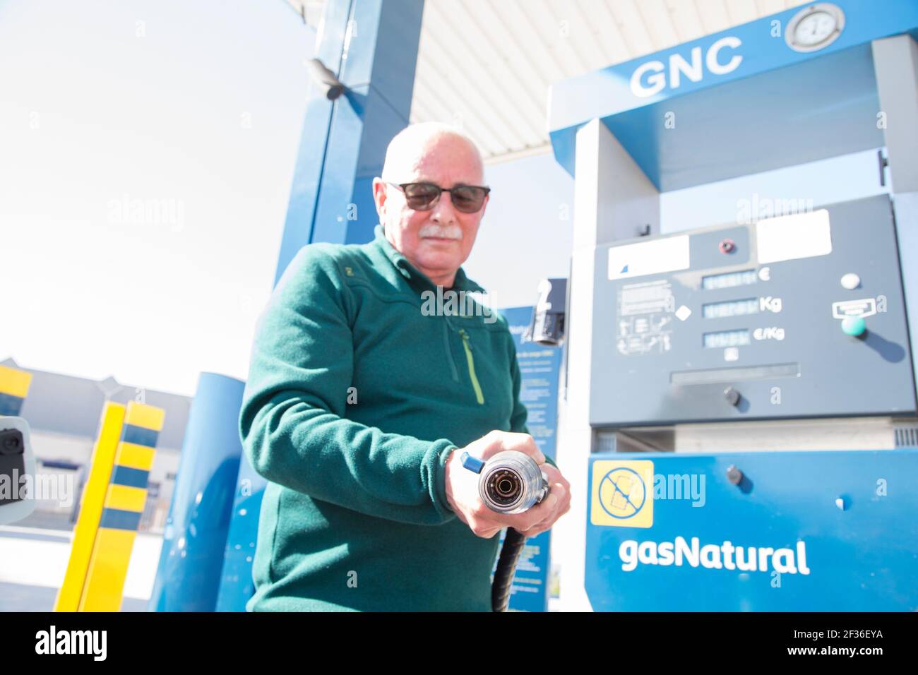 Older man in green sweater and jeans holding a compressed natural gas ...
