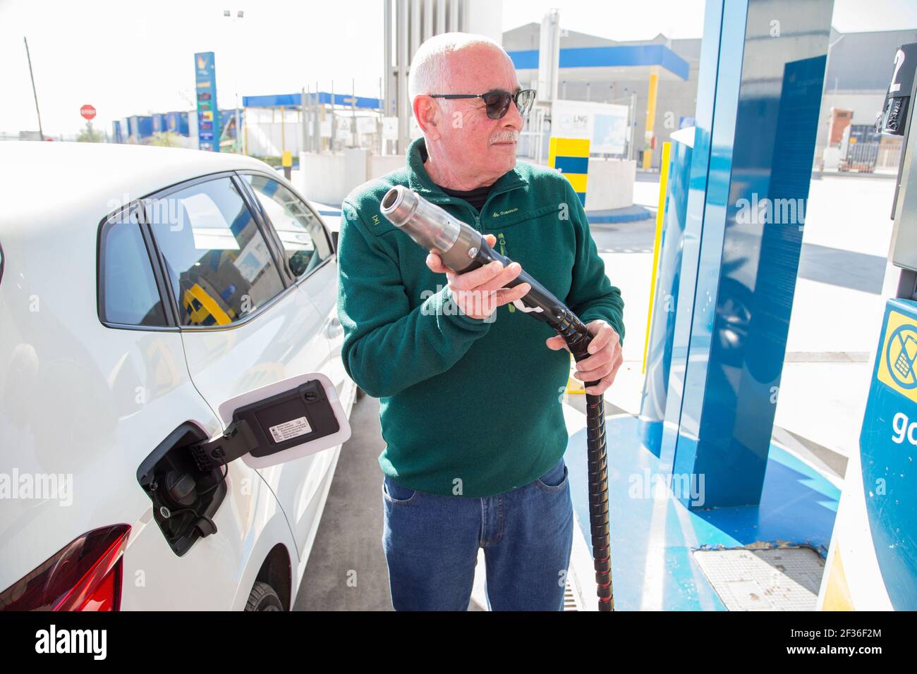 Old man in a green sweater and jeans holding a compressed natural gas ...