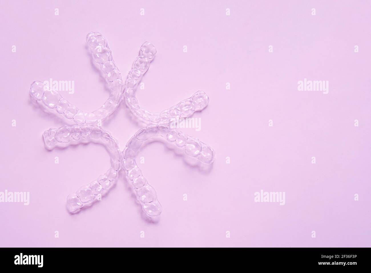 Invisible aligner teeth retainers on a pink background Stock Photo - Alamy