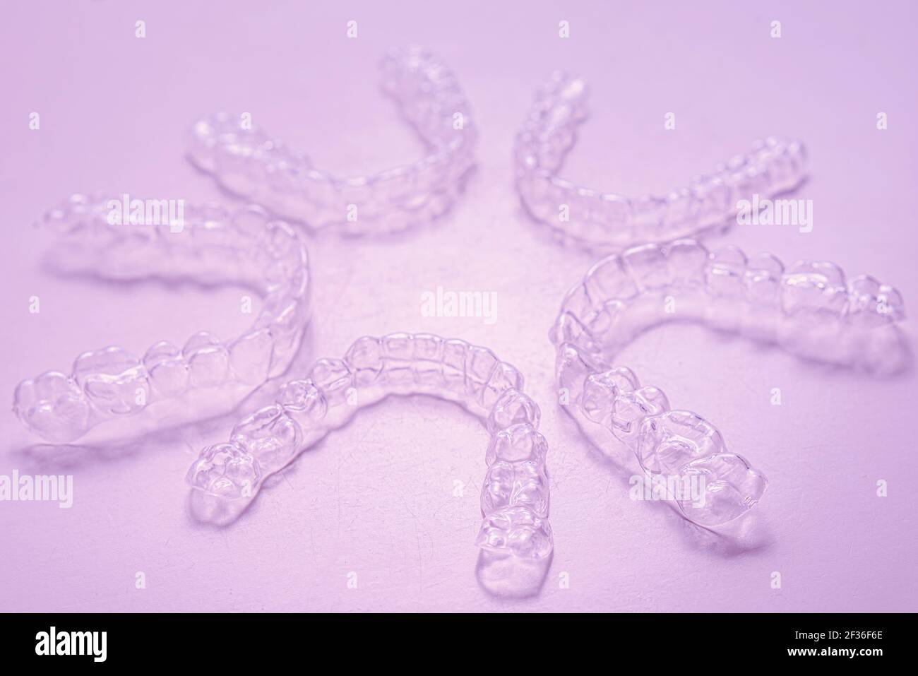 Invisible aligner teeth retainers on a pink background Stock Photo - Alamy