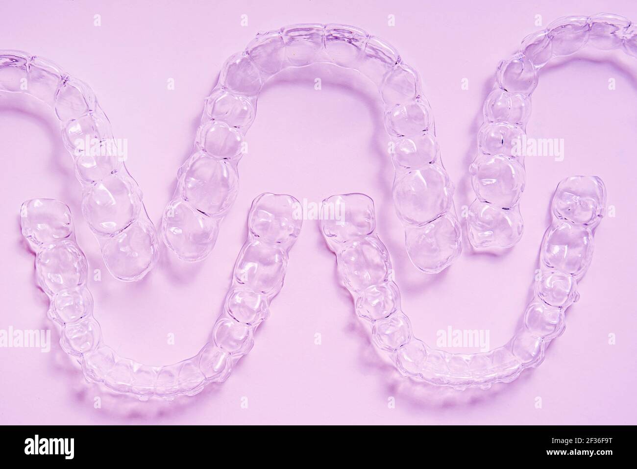 Invisible aligner teeth retainers on a pink background Stock Photo - Alamy