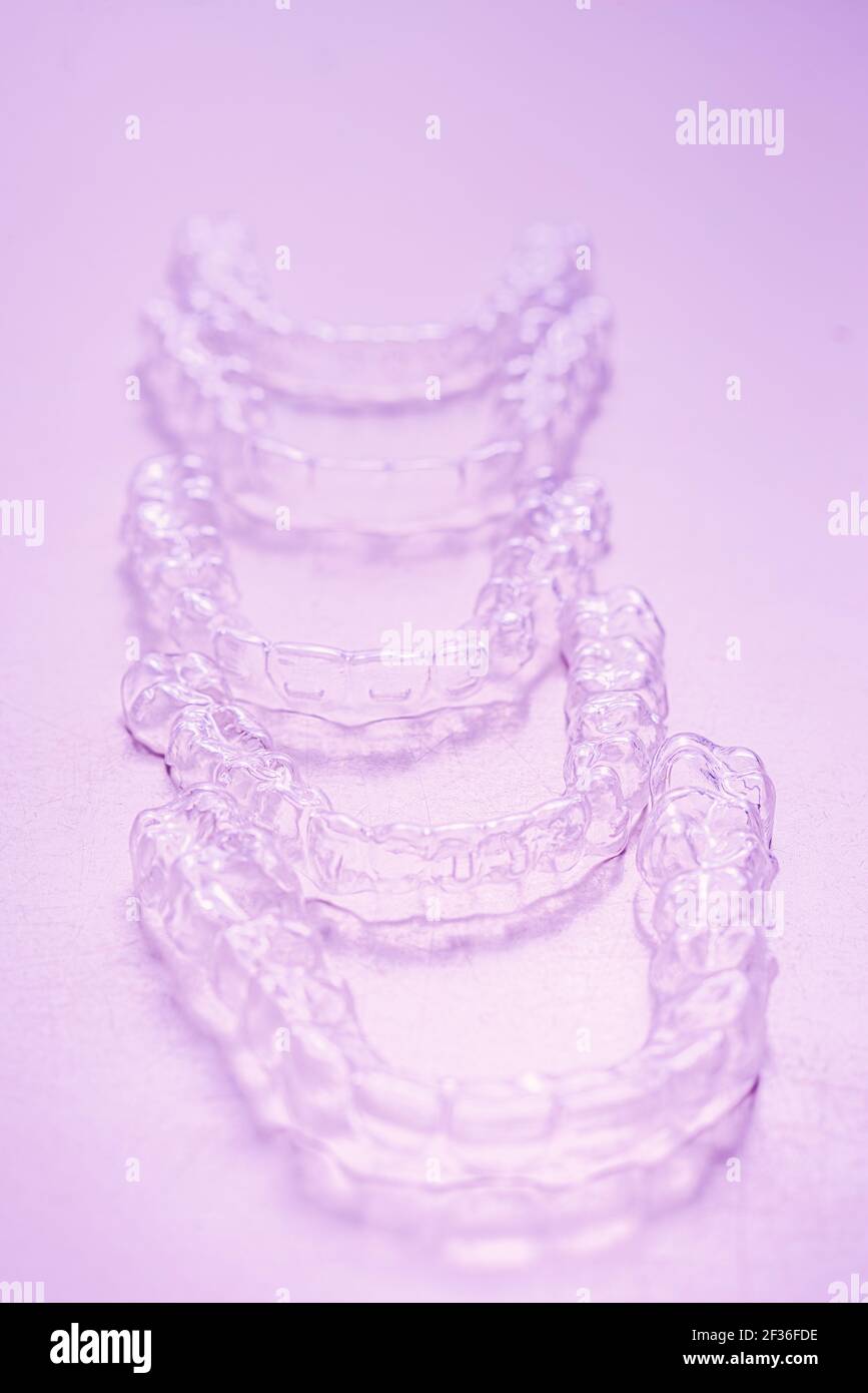 Invisible aligner teeth retainers on a pink background Stock Photo - Alamy