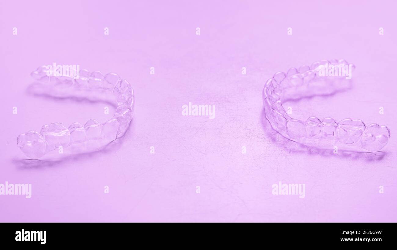 Invisible aligner teeth retainers on a pink background Stock Photo - Alamy
