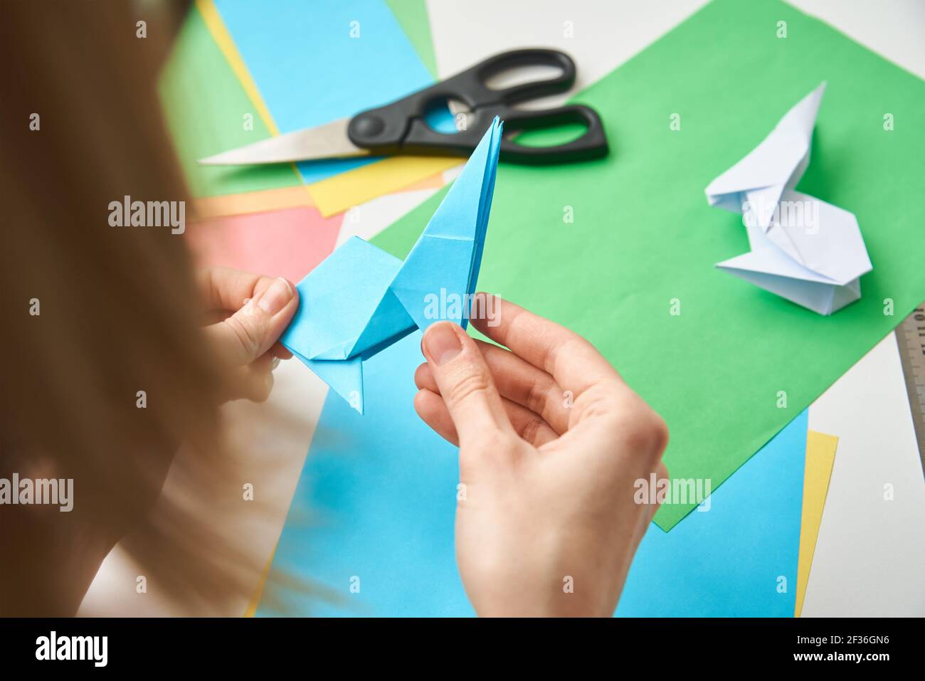 Origami lessons. Woman make origami easter rabbit from color paper. DIY ...