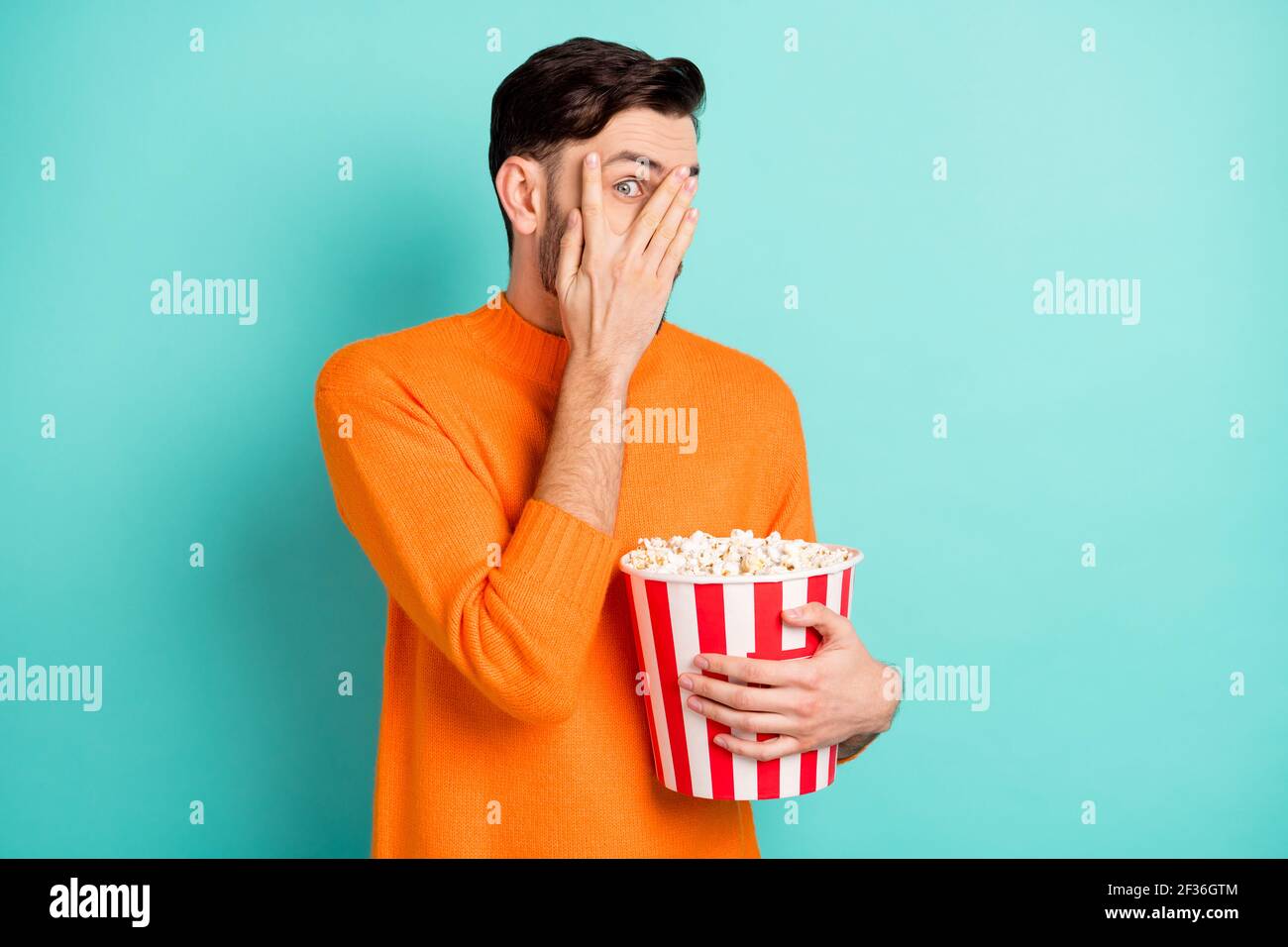 Photo of young guy close cover face hand hold popcorn box watch horror ...