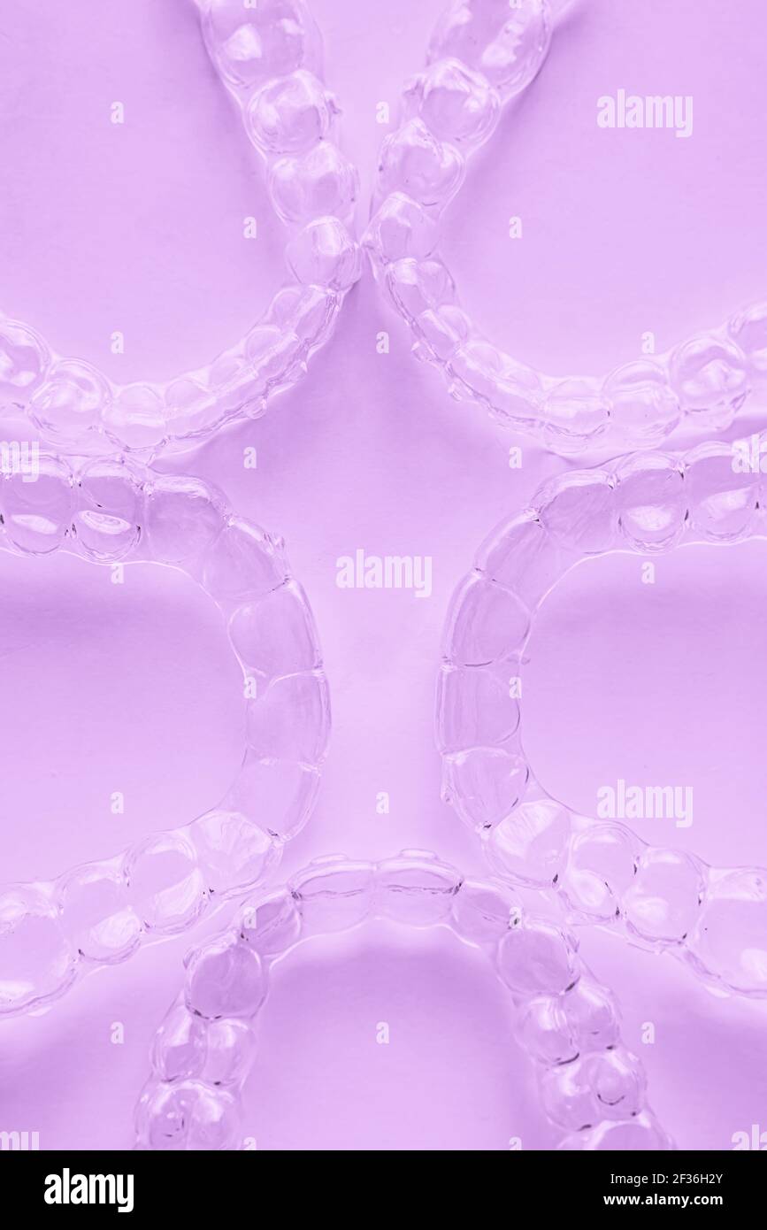 Invisible aligner teeth retainers on a pink background Stock Photo - Alamy
