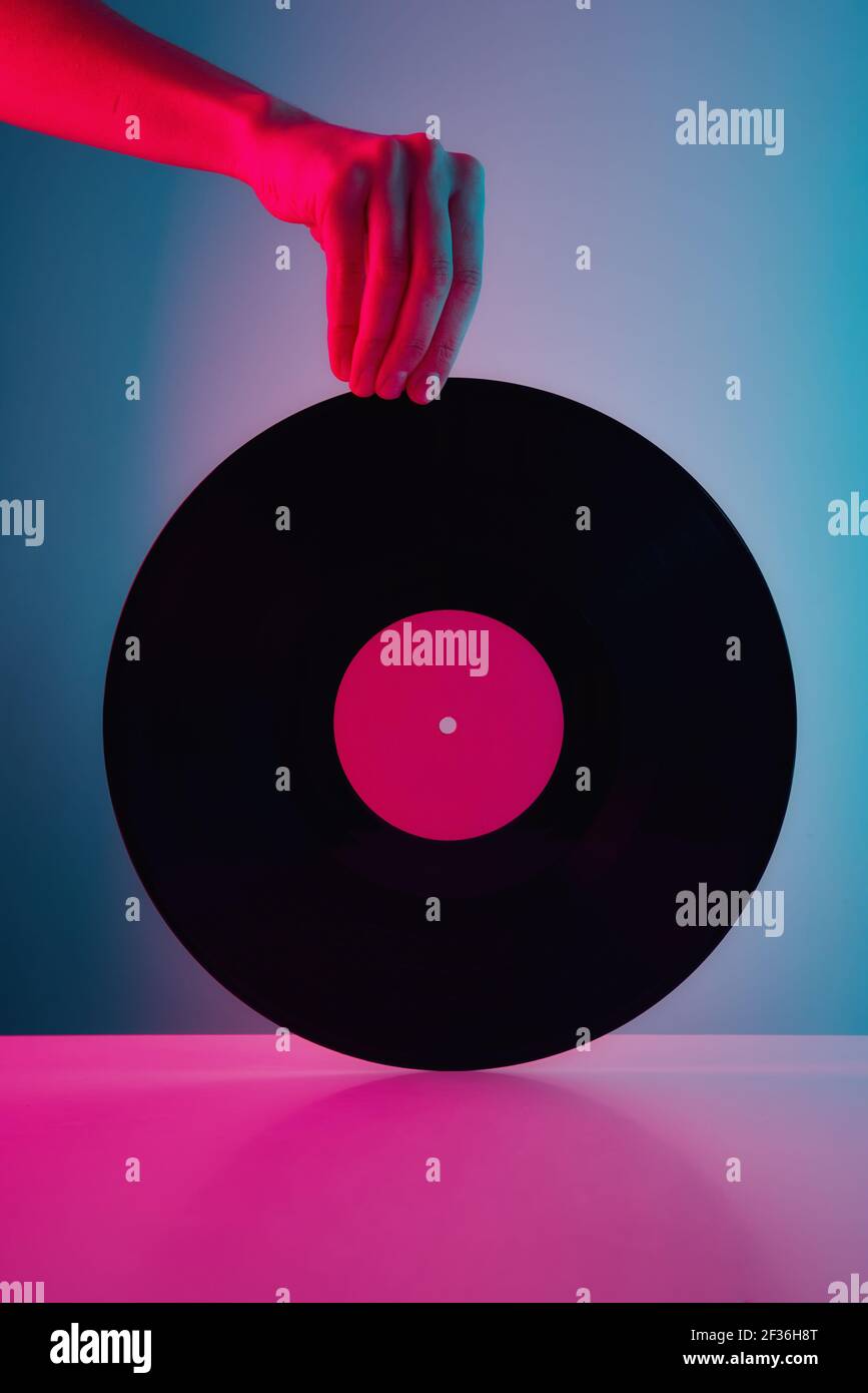 Hand holds retro vinyl disc with neon lights. Vintage music background ...