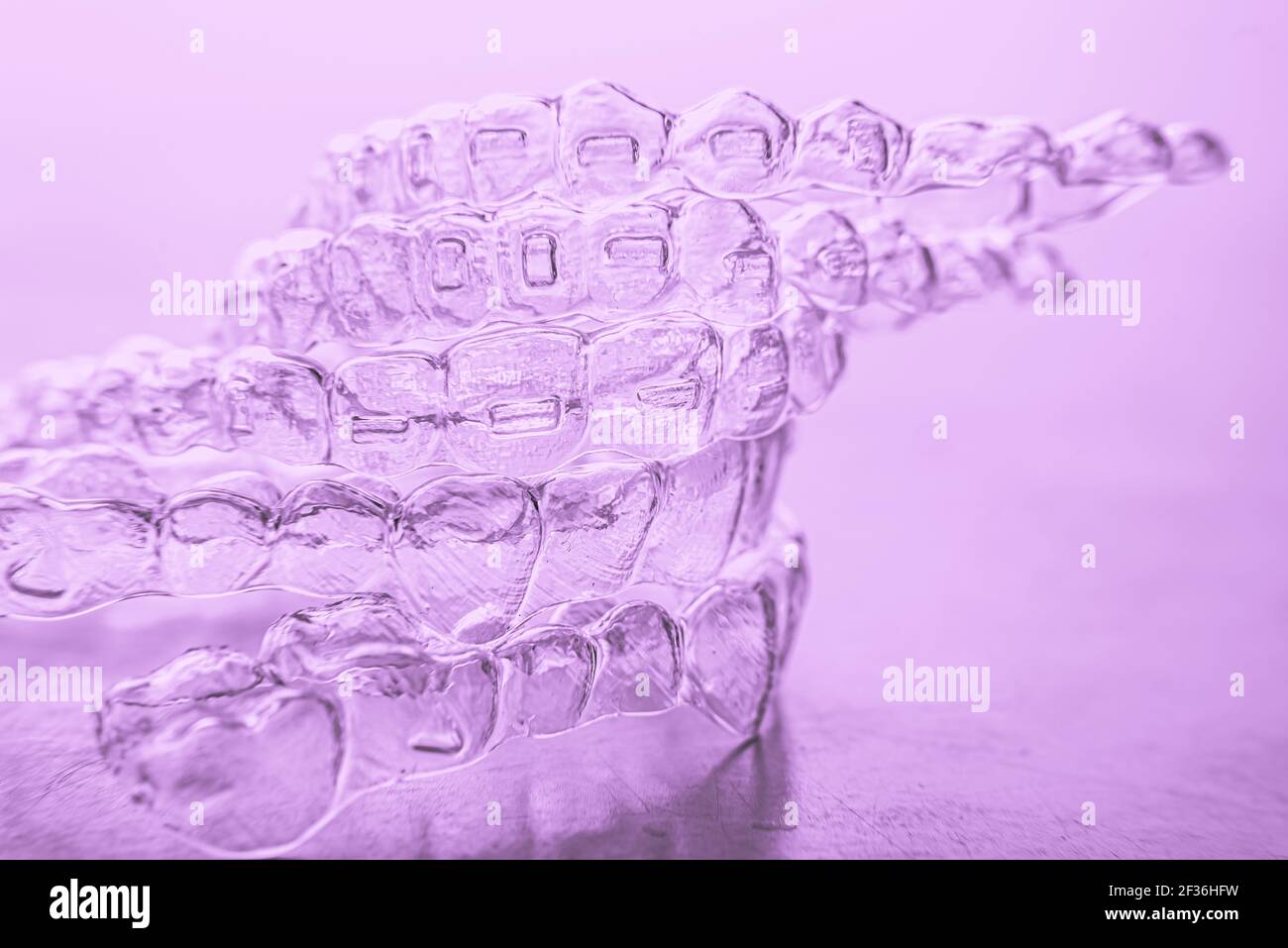 Invisible aligner teeth retainers on a pink background Stock Photo - Alamy