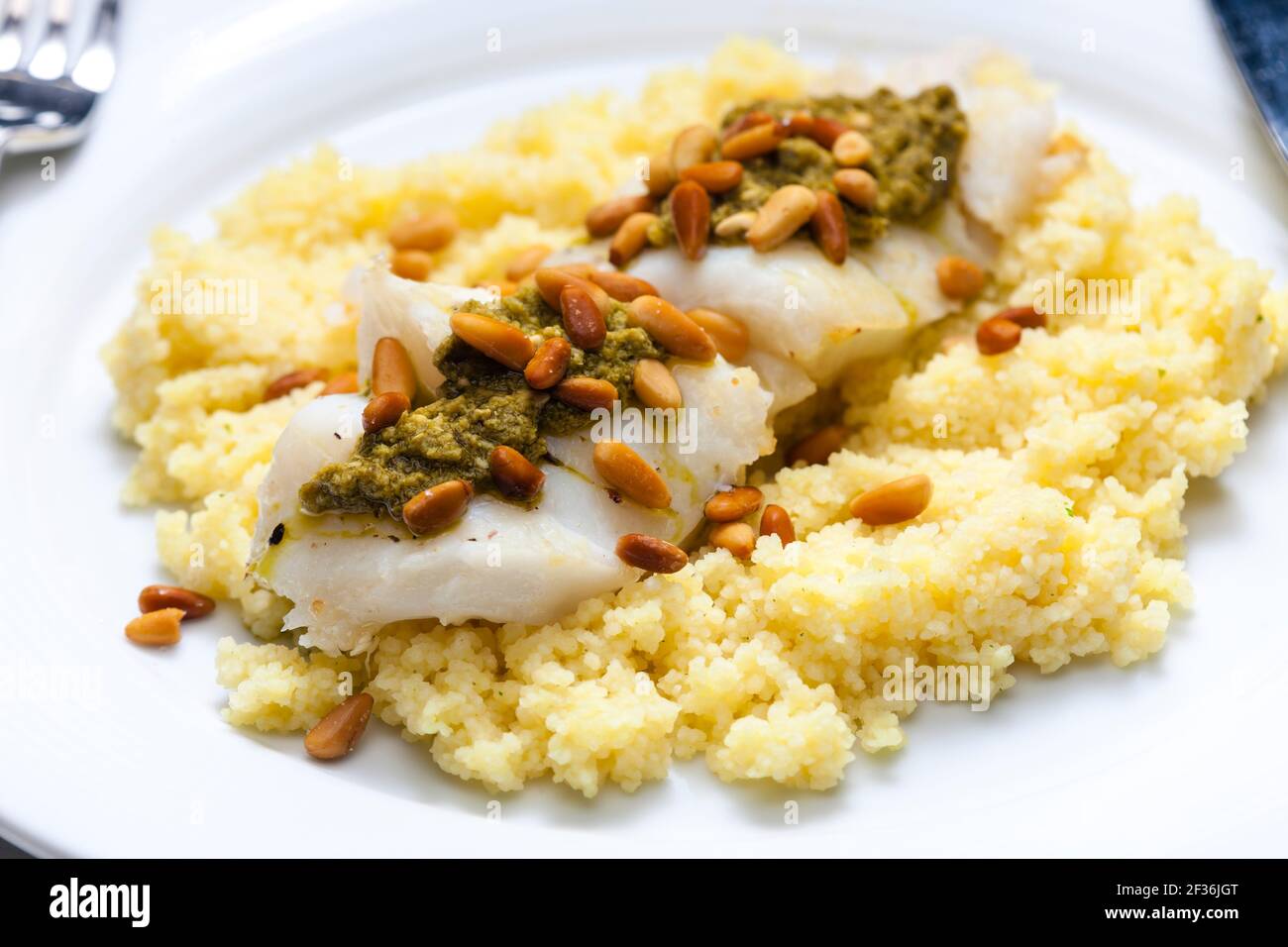 cod with green pesto and pine seeds with couscous Stock Photo - Alamy