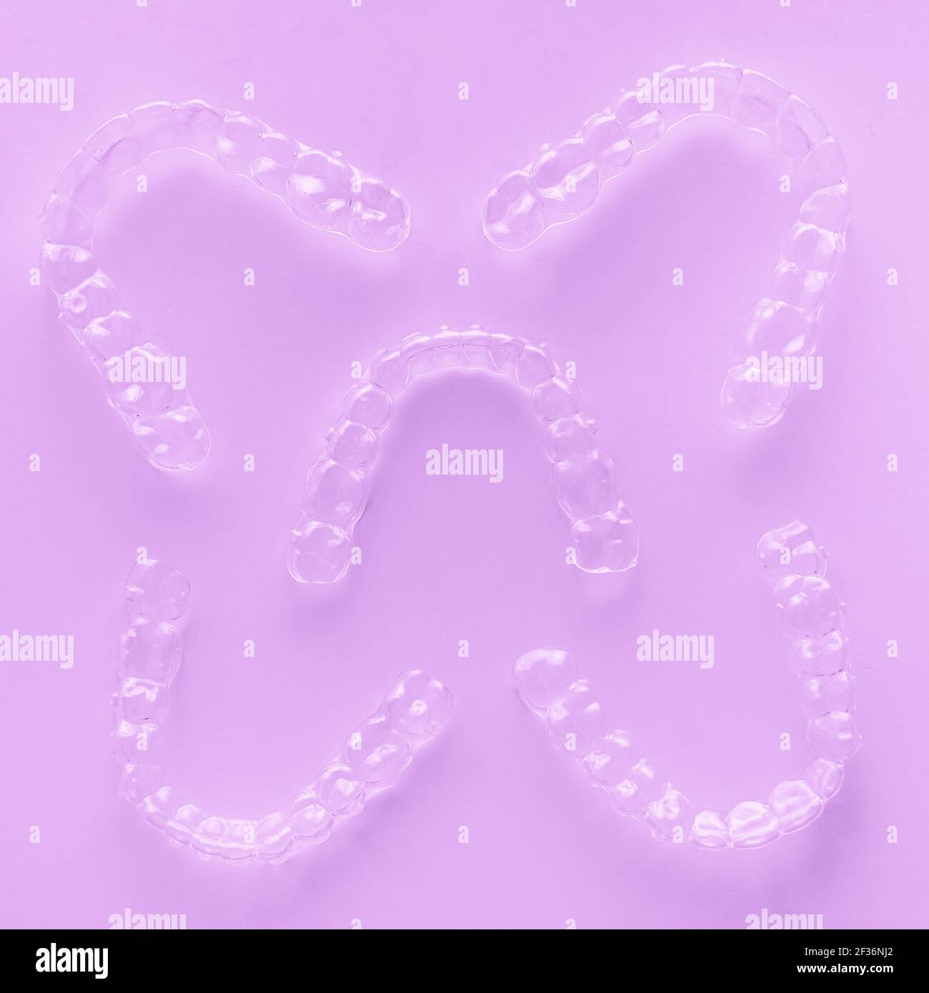 Invisible aligner teeth retainers on a pink background Stock Photo - Alamy
