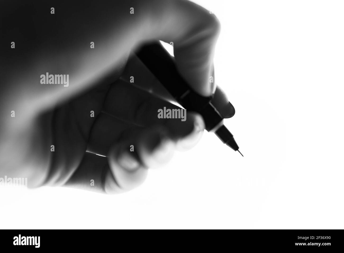 Pen in a female hand on a white background. Side view, selective focus ...