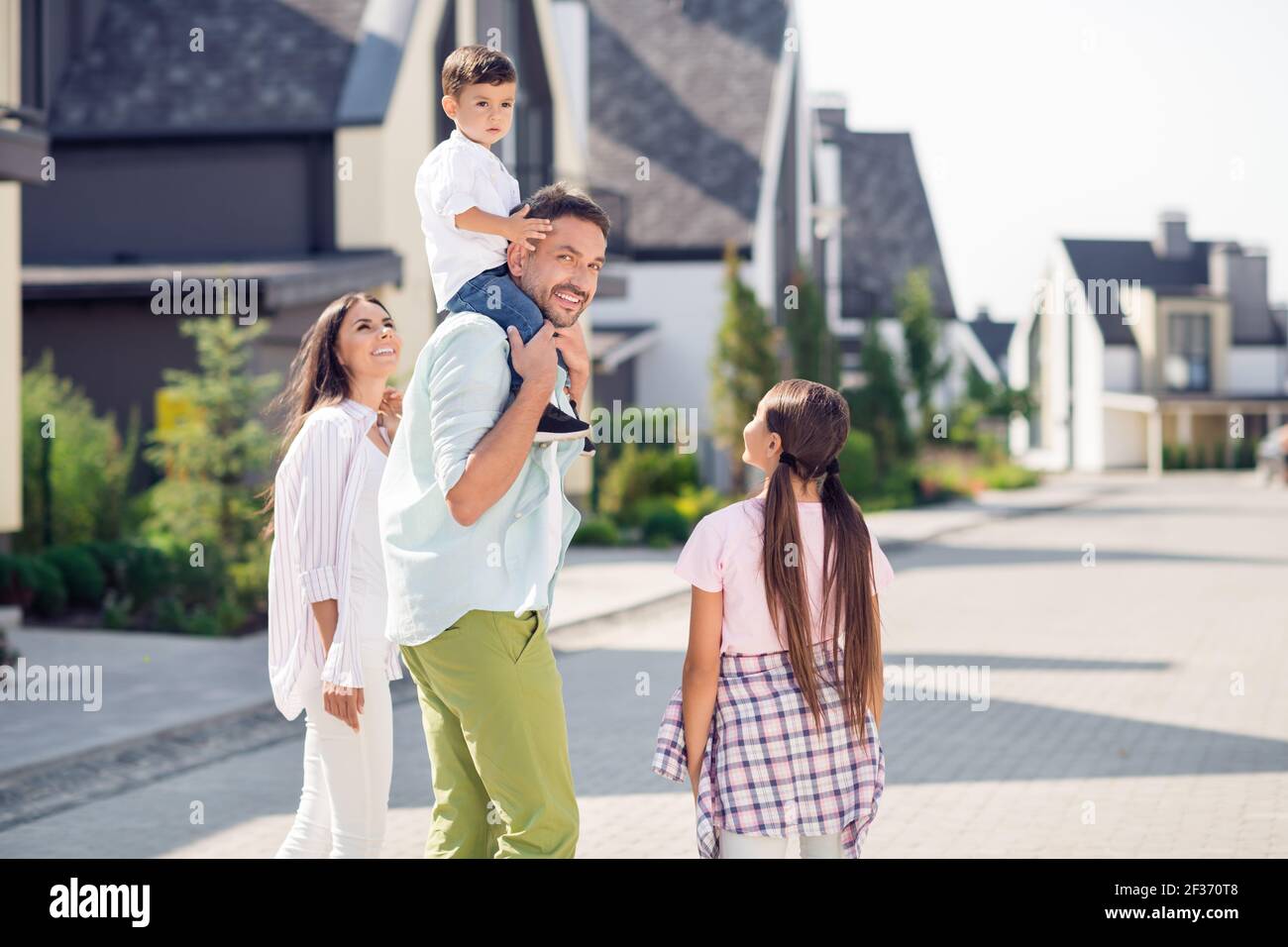 Back rear spine view photo of happy smiling family walk on street dad ...