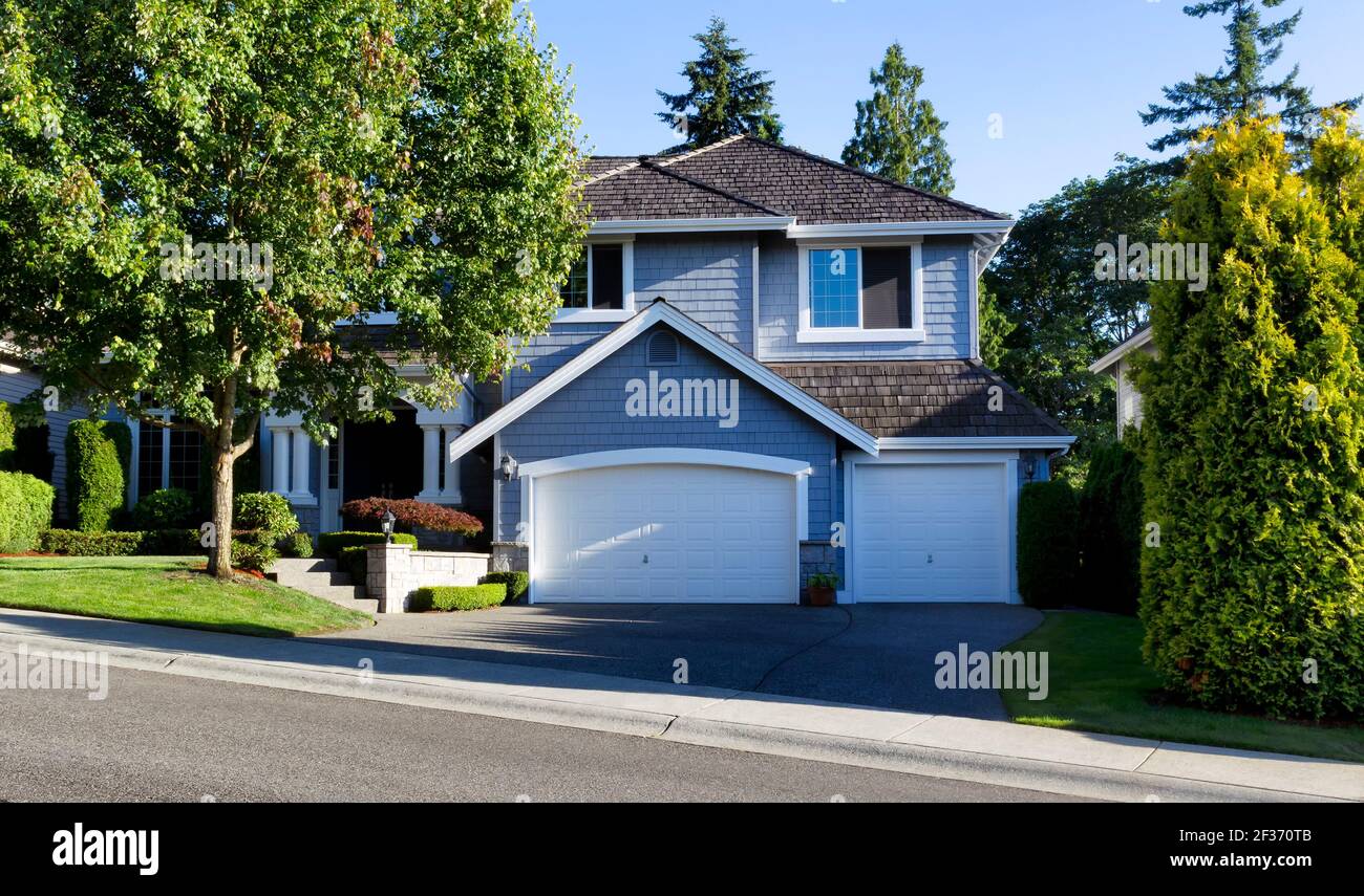 Curb view of a modern home with cedar shake roof during summer morning ...