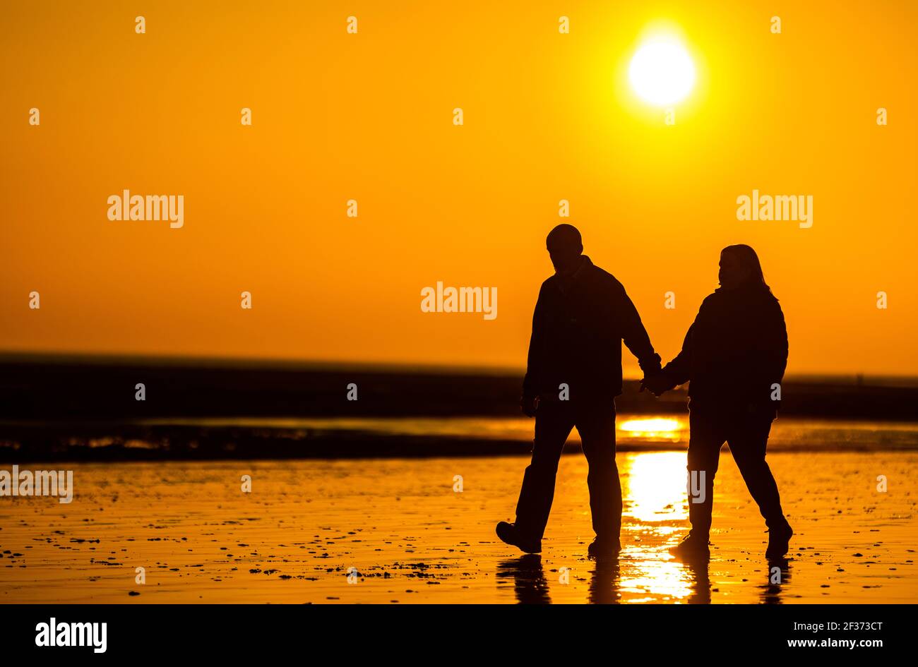 The rising sunrise as birds fly and people walk their dog at Rustington ...