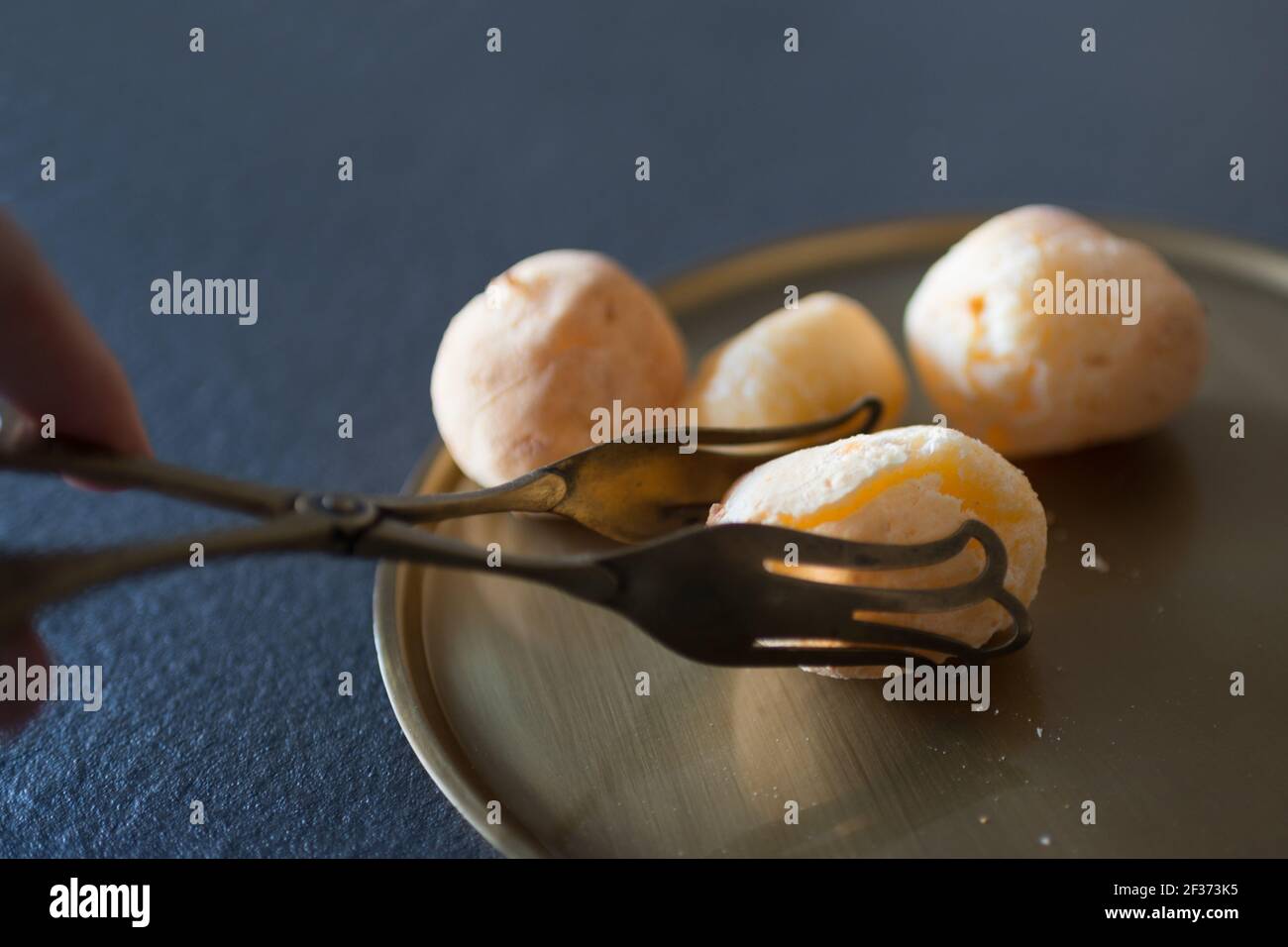 Bronze platter with delicious cheese appetizers and a hand taking one ...