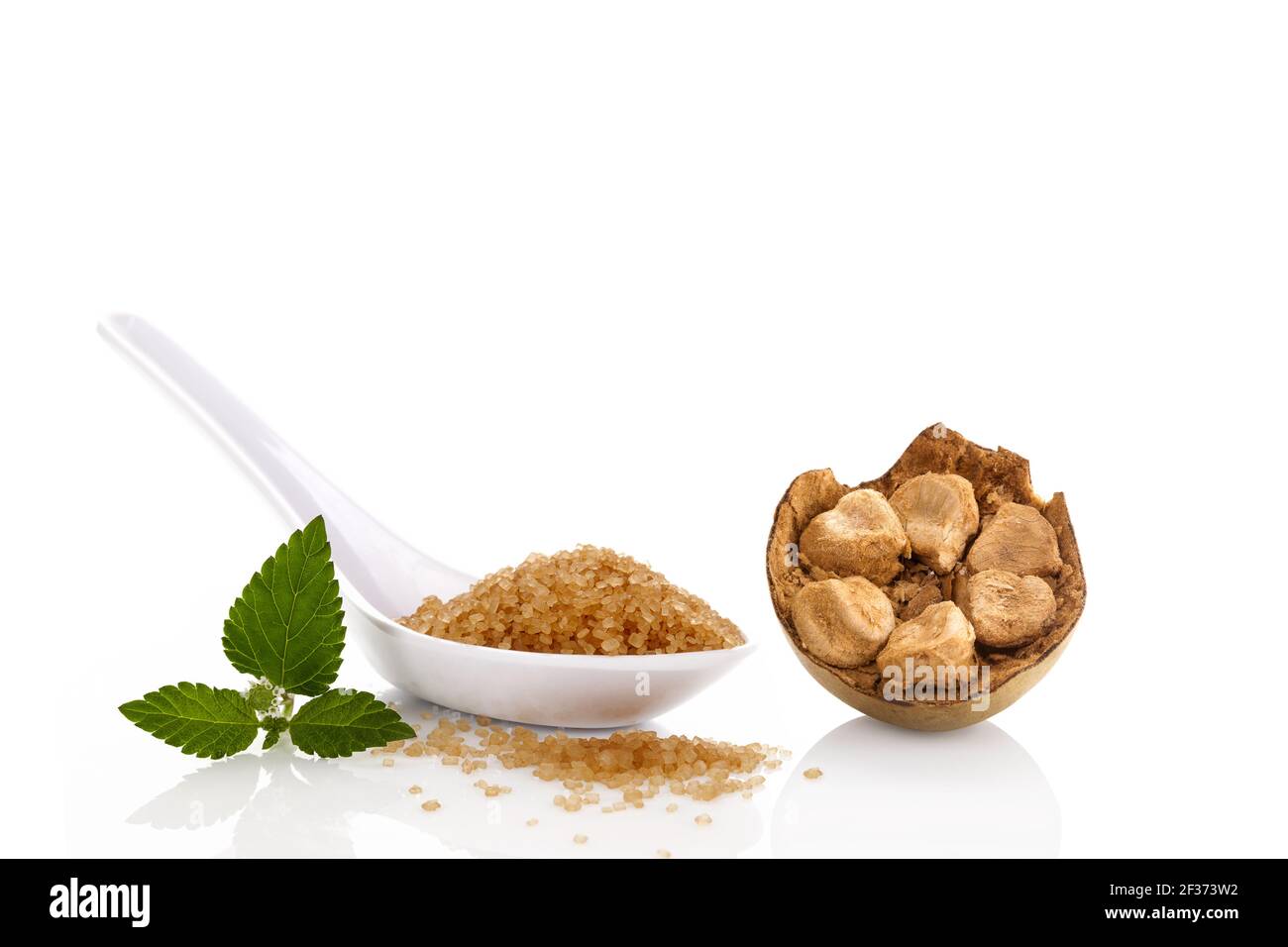 Heap of brown cane crystallized sugar in white spoon and monk fruit ...