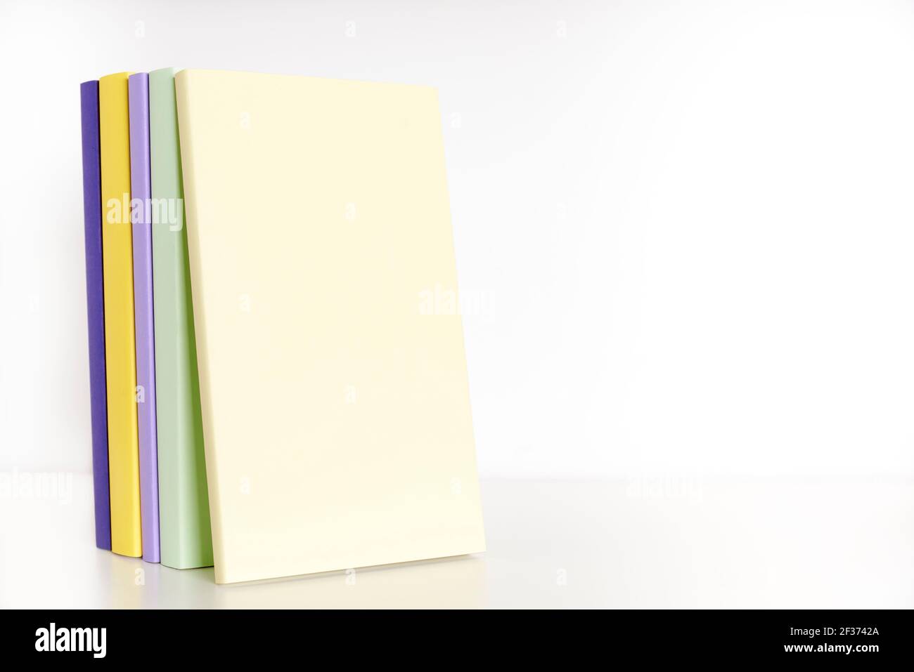 Colored books with blank spine on a white shelf with white background ...