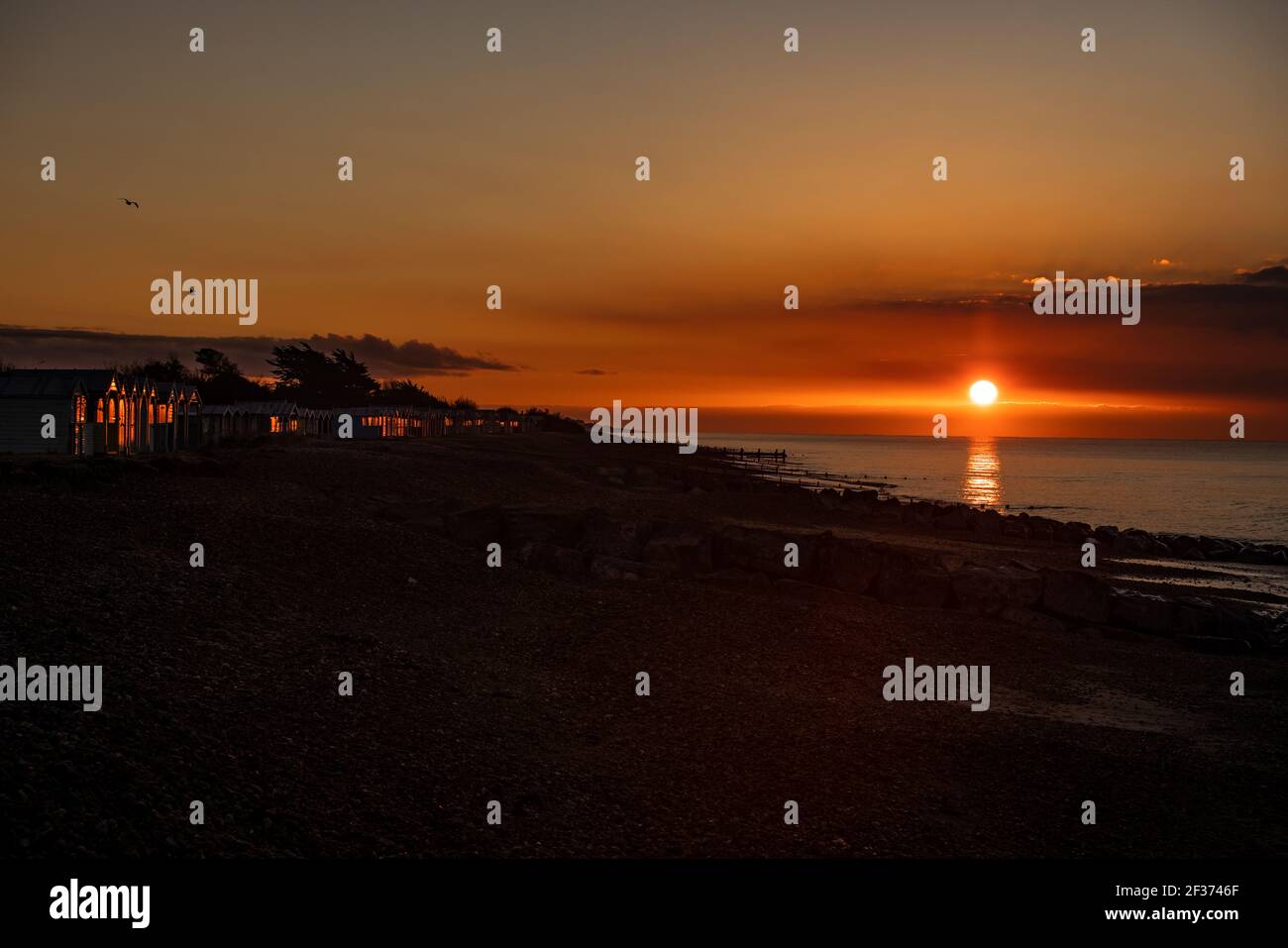 The rising sunrise reflected off beach huts at Rustington in West ...