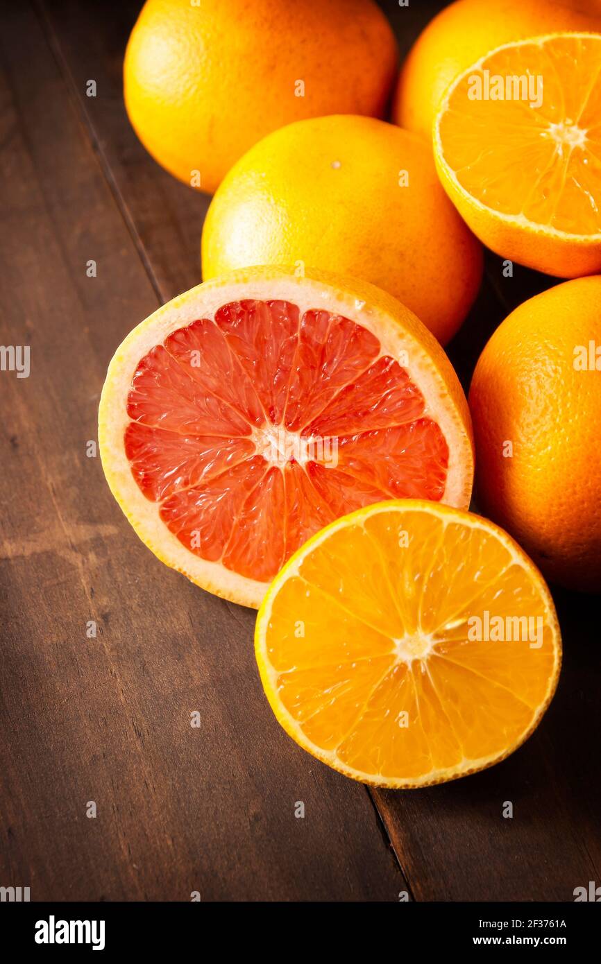 ripe orange and grapefruit slices and several whole oranges on brown ...