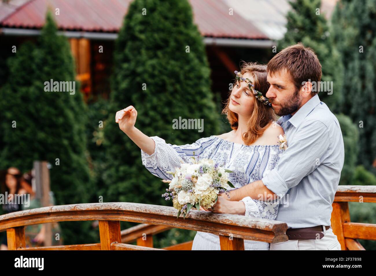 Eclectic rustic wedding couple stand on the bridge Stock Photo - Alamy