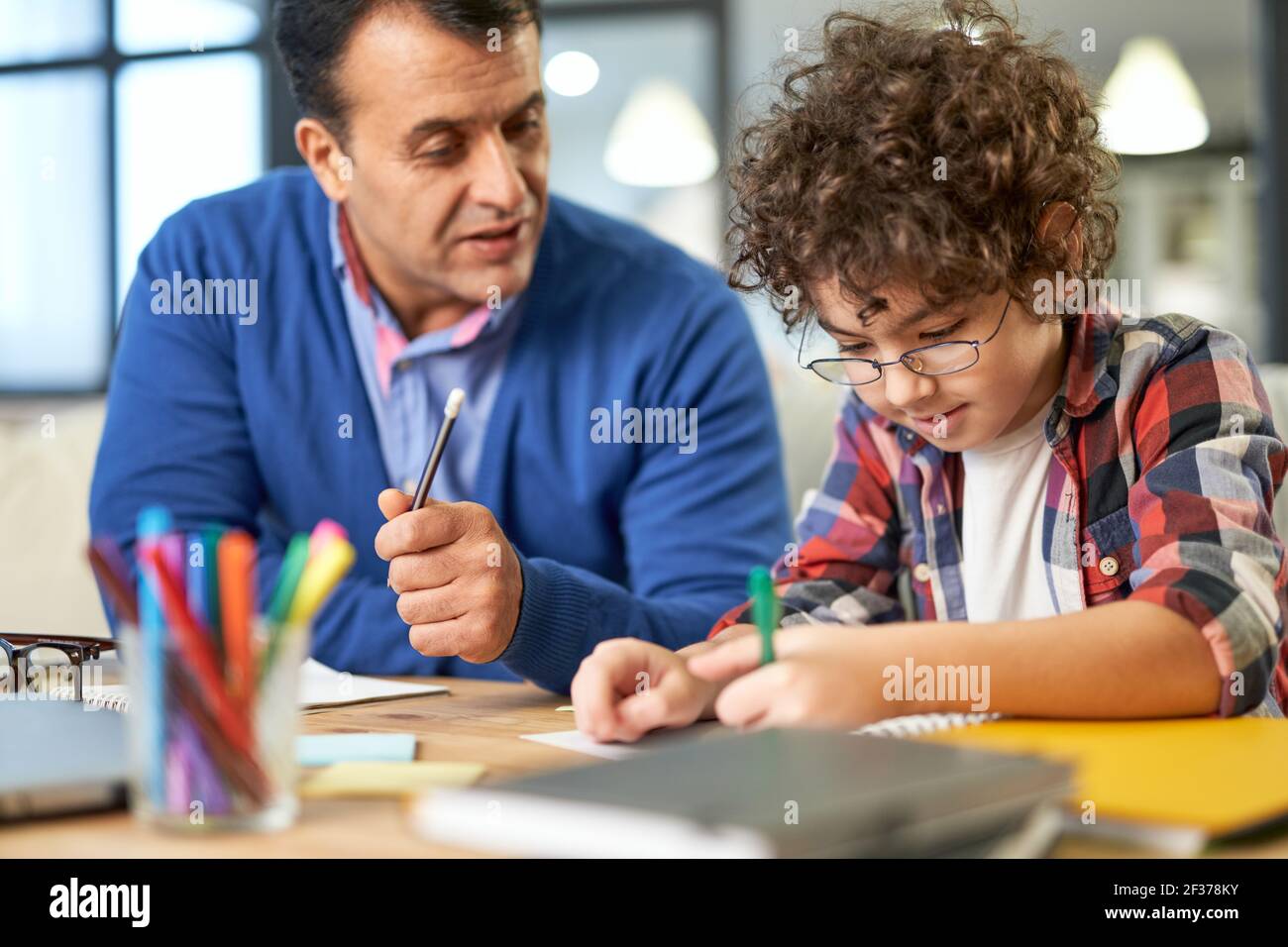 Learning together. Portrait of caring middle aged latin father helping ...