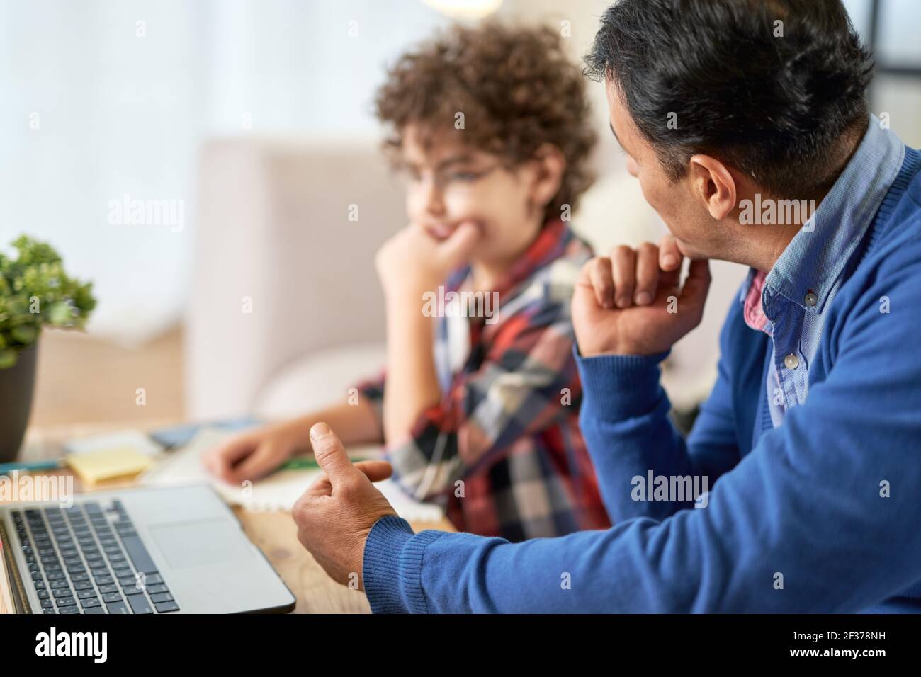Latin middle aged father helping his cute son, school boy with studies ...